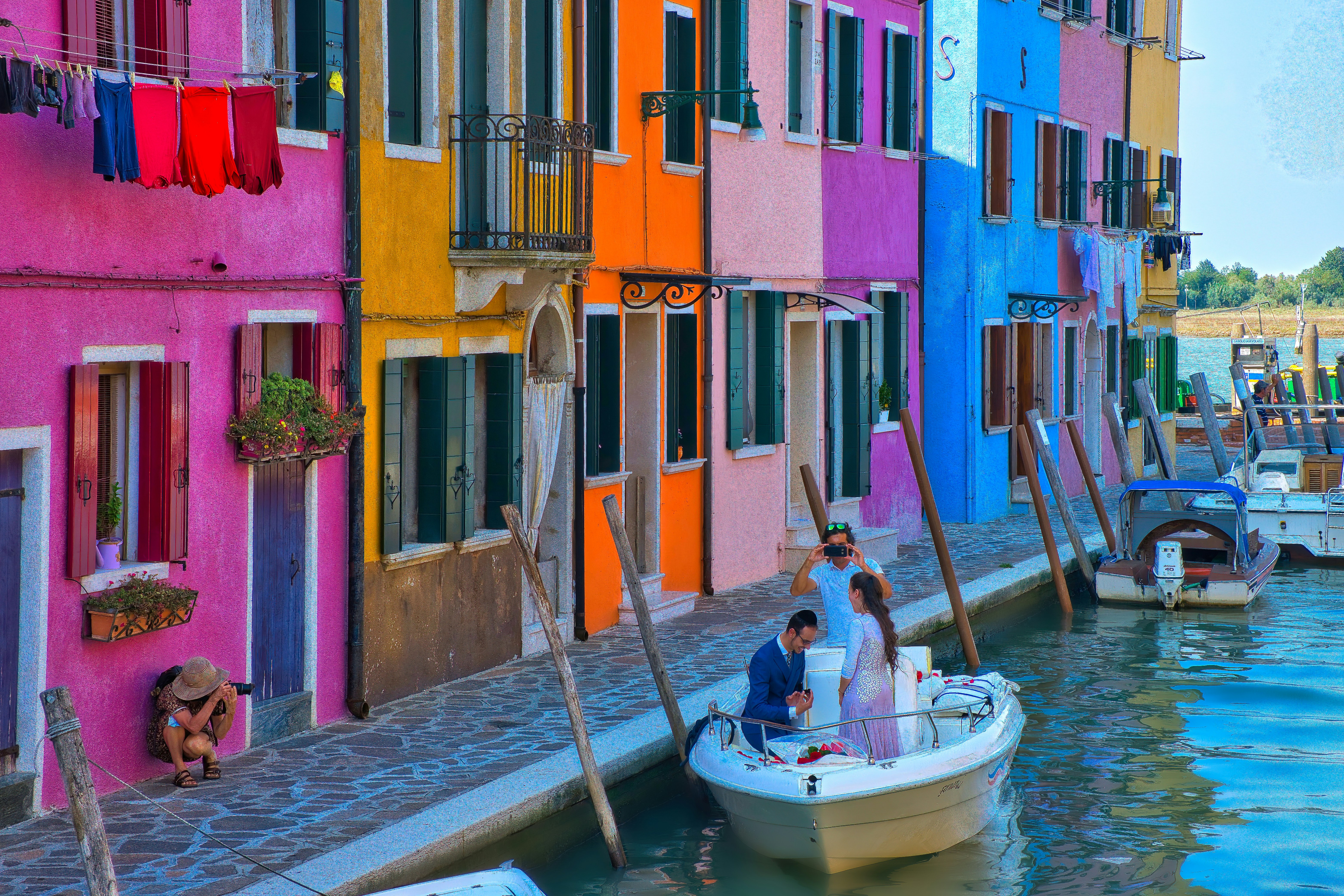 Vivid Canalside Portrait: A Couple in a White Boat Amid Rainbow Facades
