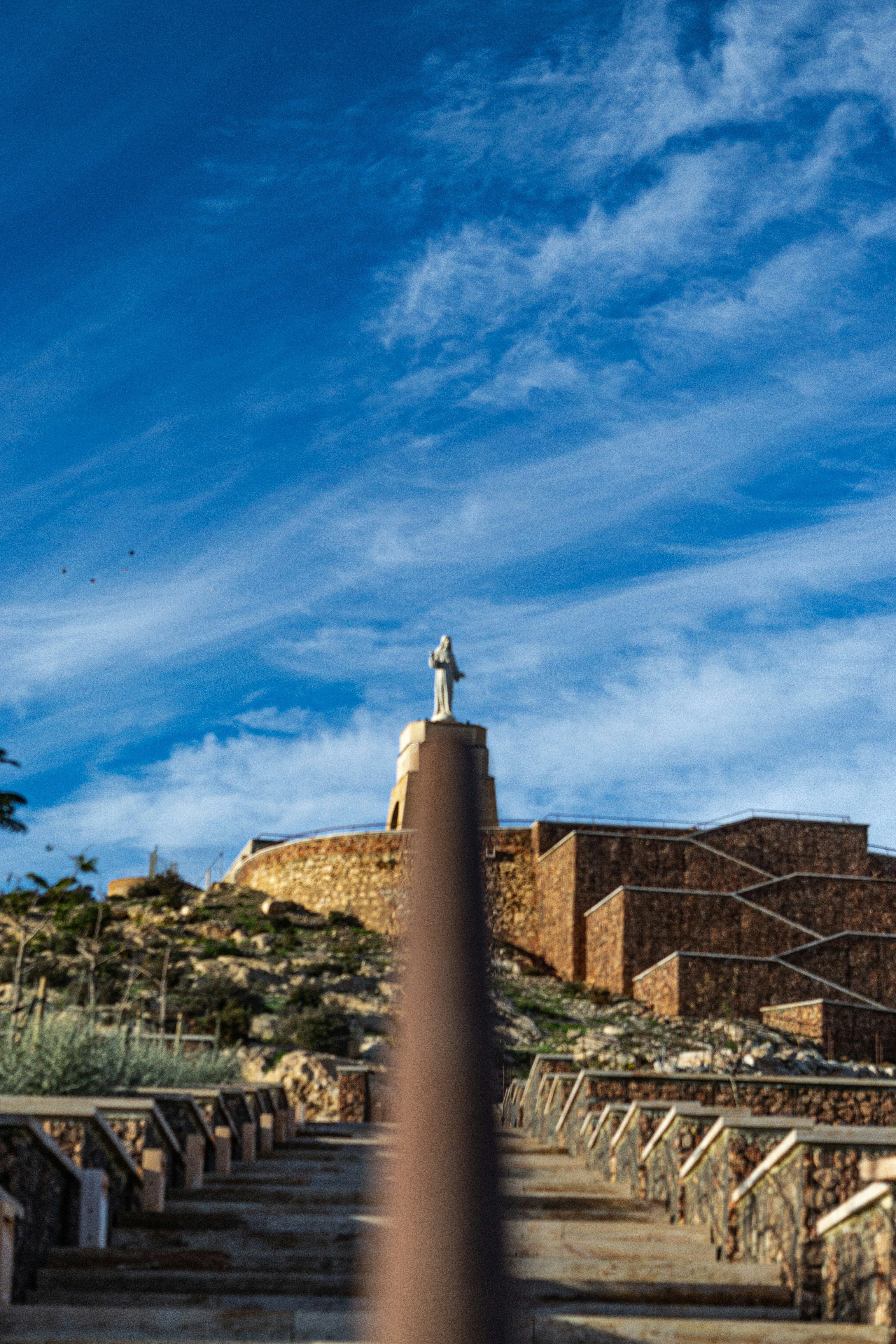 Statue at the Summit: A Solitary Figure Overlooking A Terraced Fortification