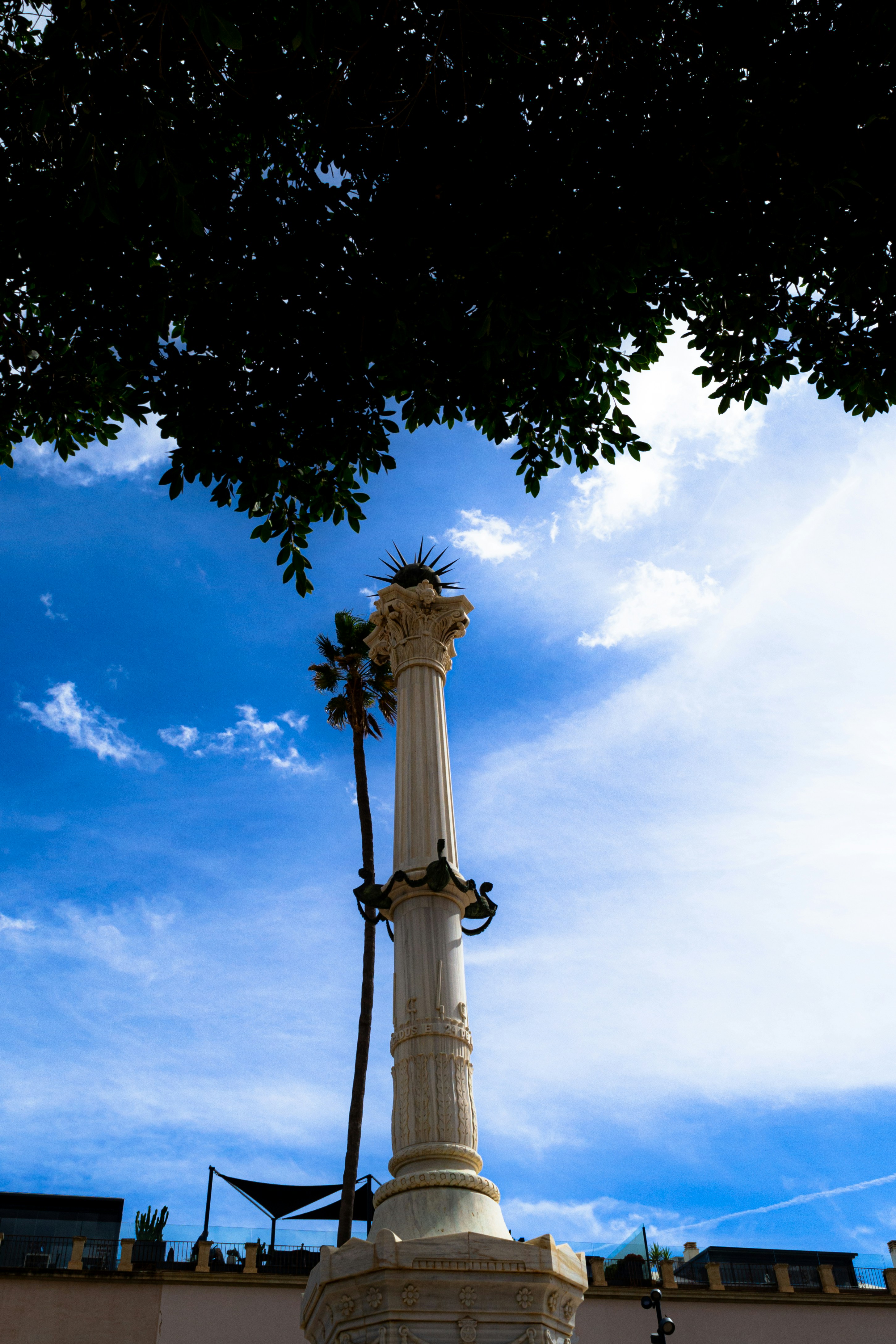 Sunlit Monument Reaches Toward the Sky Under a Veil of Leaves