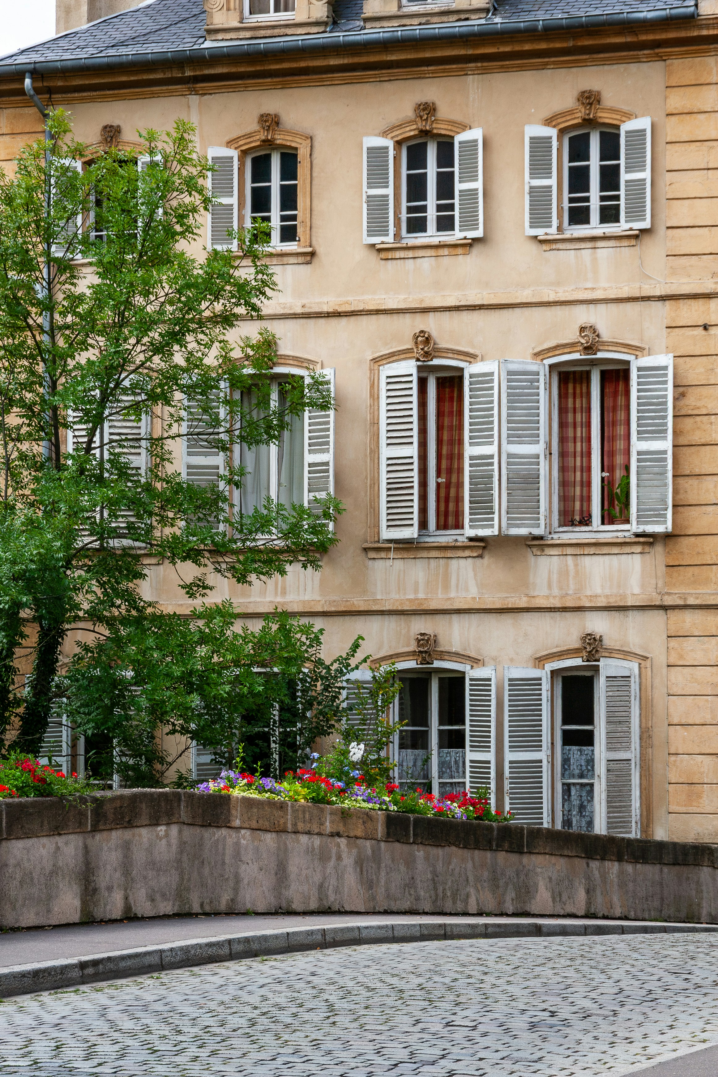 Sunlit Parisian Facade: Shuttered Windows and Walled Balcony Rows