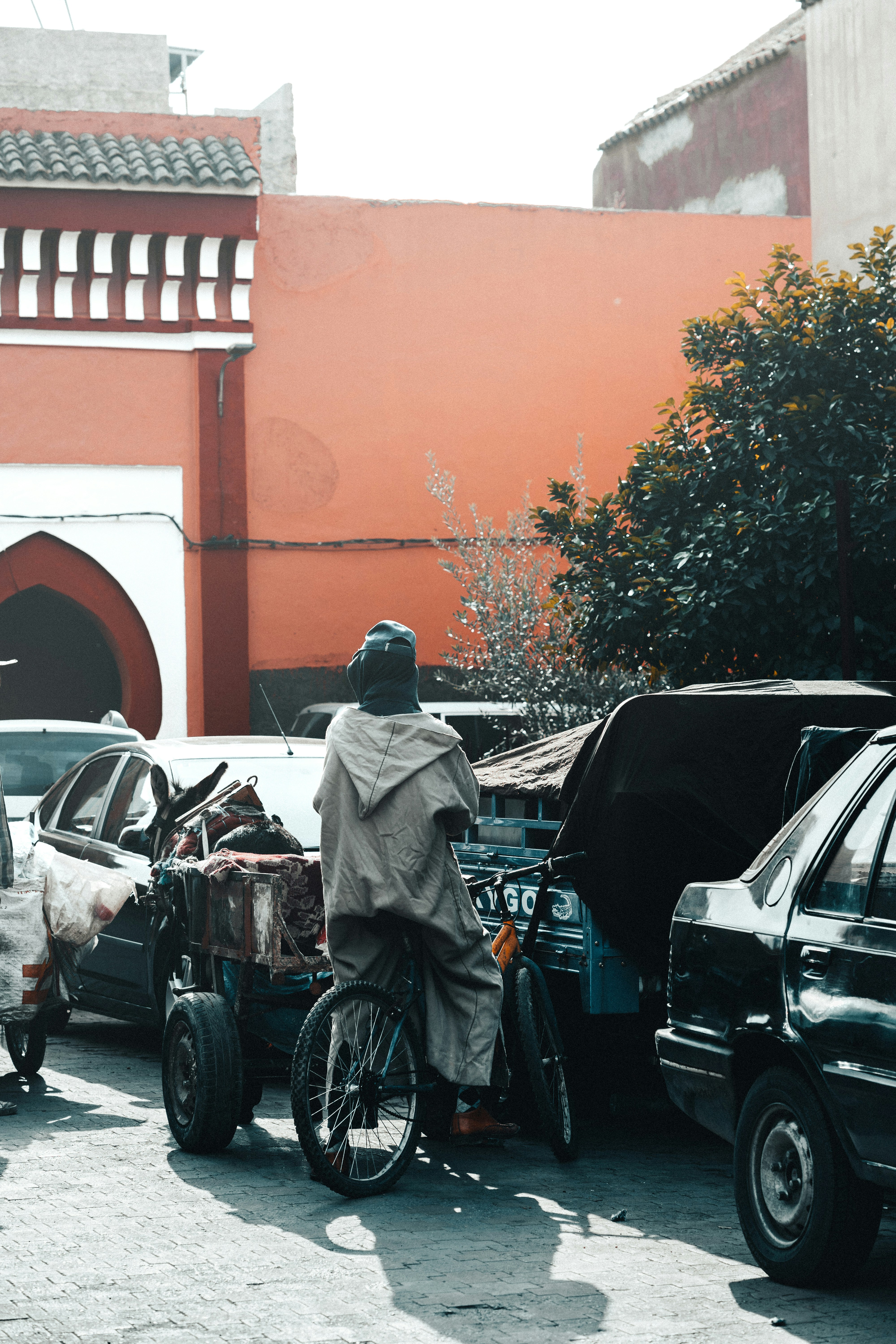 Wheelbarrow of Stories: A Street Scene with a Hooded Pedestrian