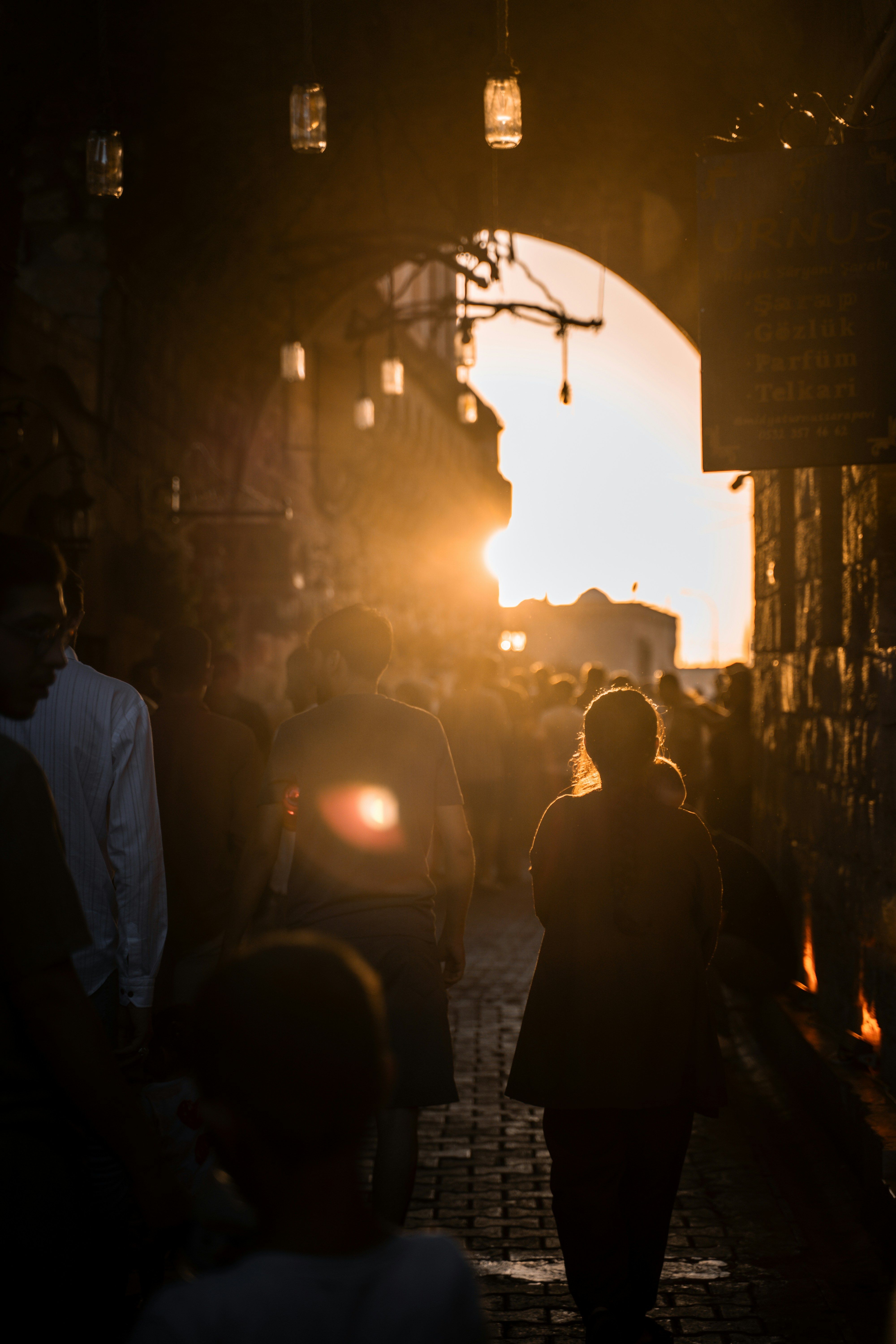 Sunlit Archway: silhouettes in a golden cobblestone alley