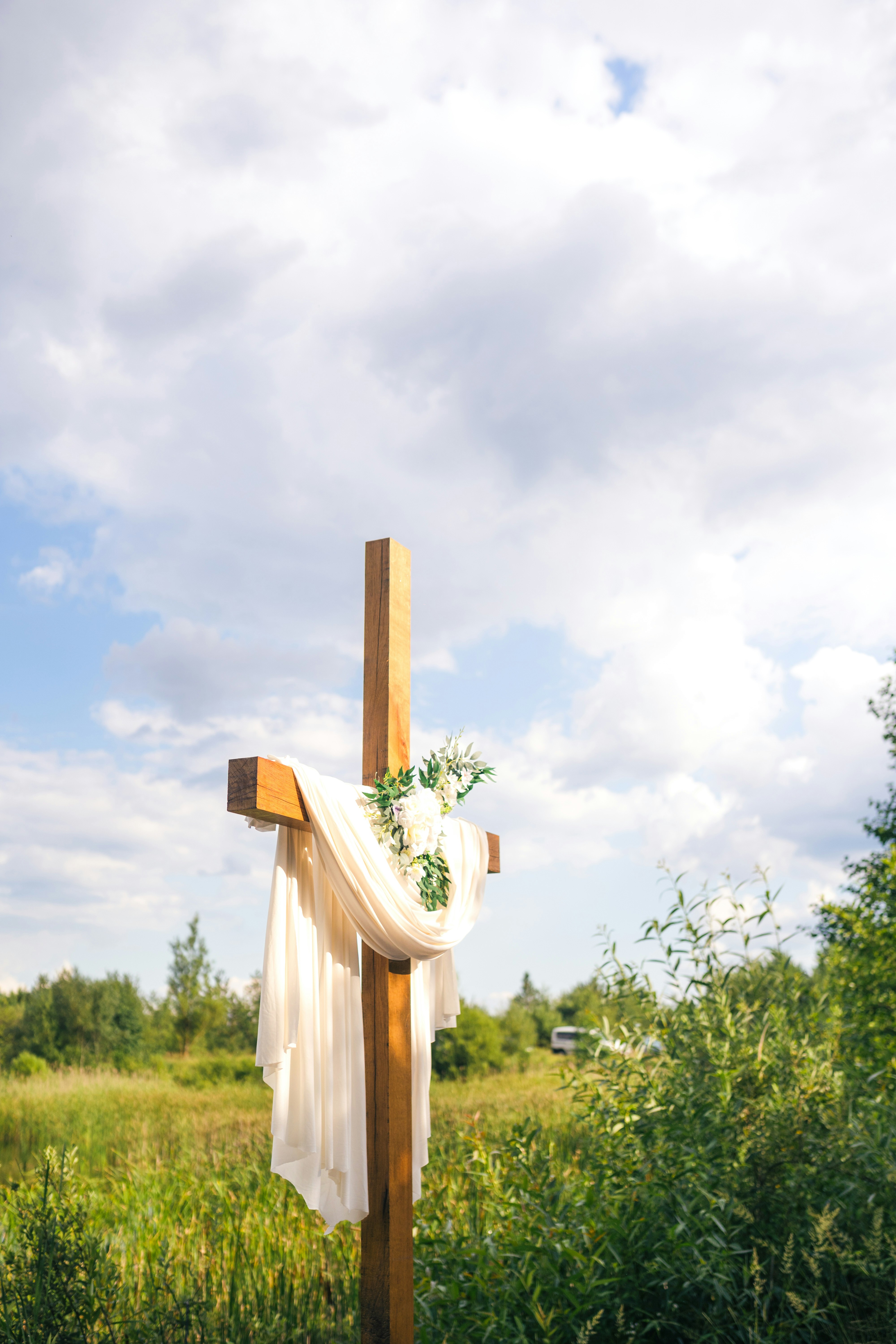 Sunlit Cross on the Field: White Drapery and Greenery