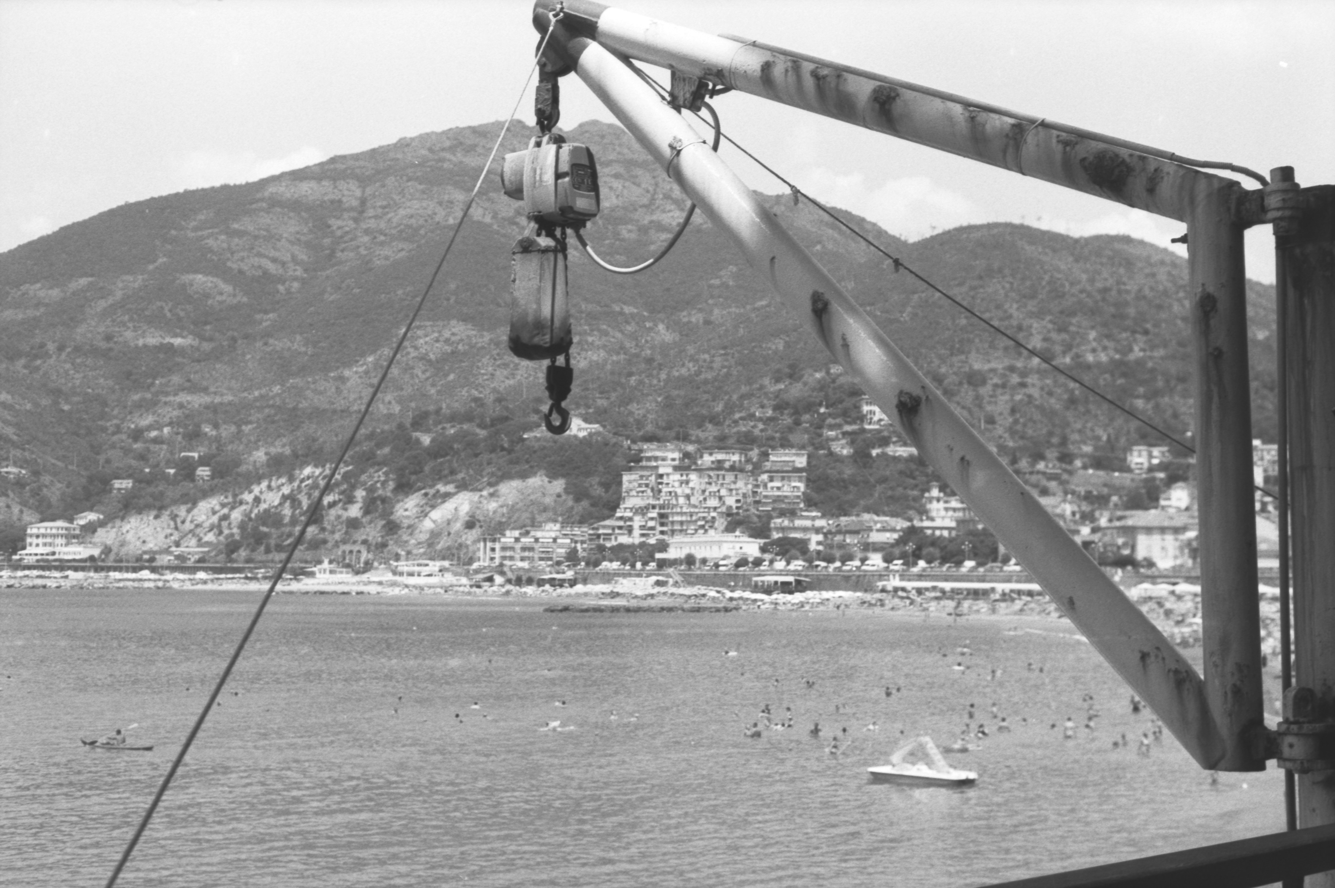 Crane Hook Over Coastal Village: Silent Machinery Framing a Seaside Scene