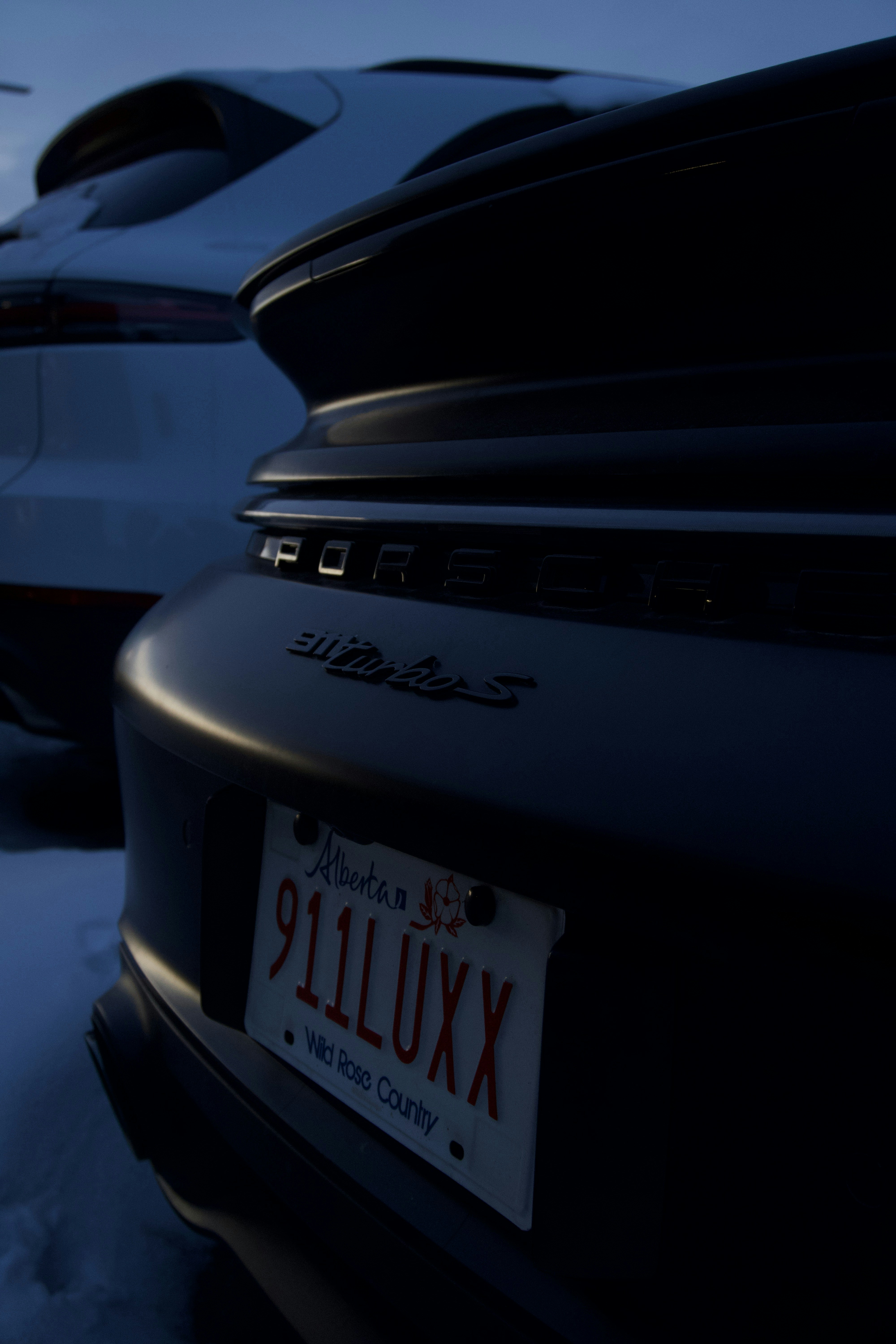 Rear View of a Porsche SUV with a Distinctive License Plate in Low Light