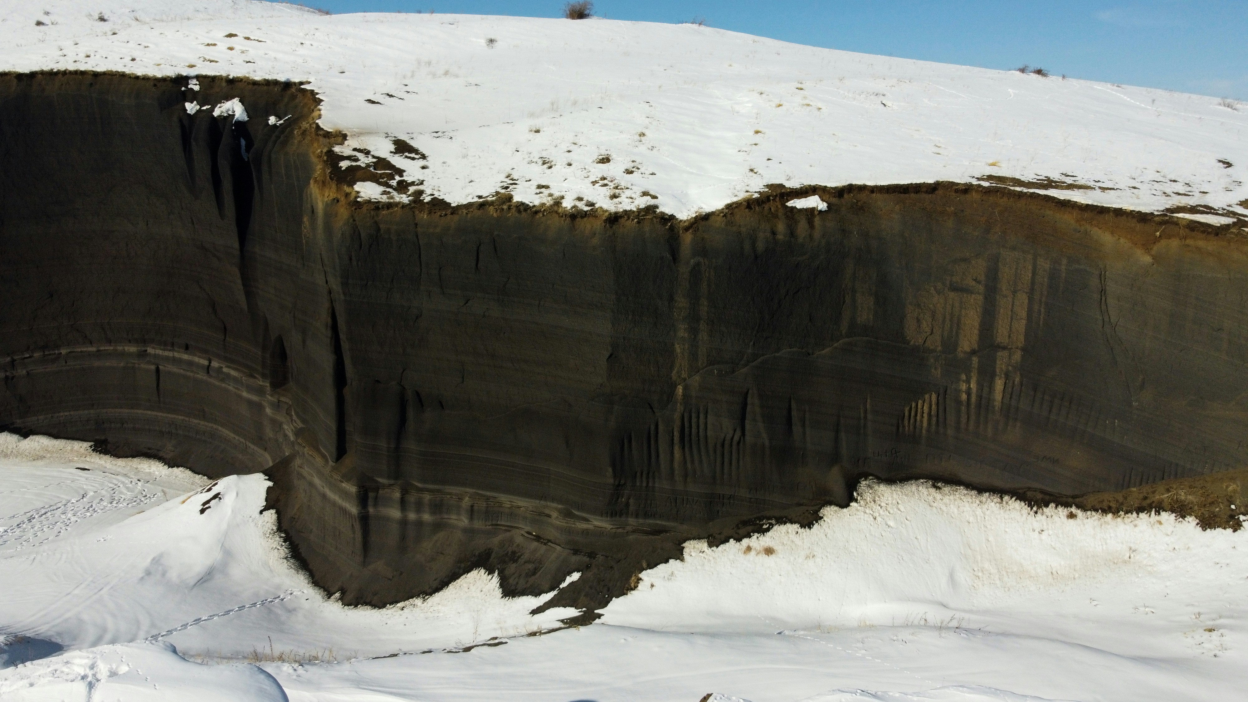 Strata of Silence: Snow-Capped Cliff Beneath a Pale Sky