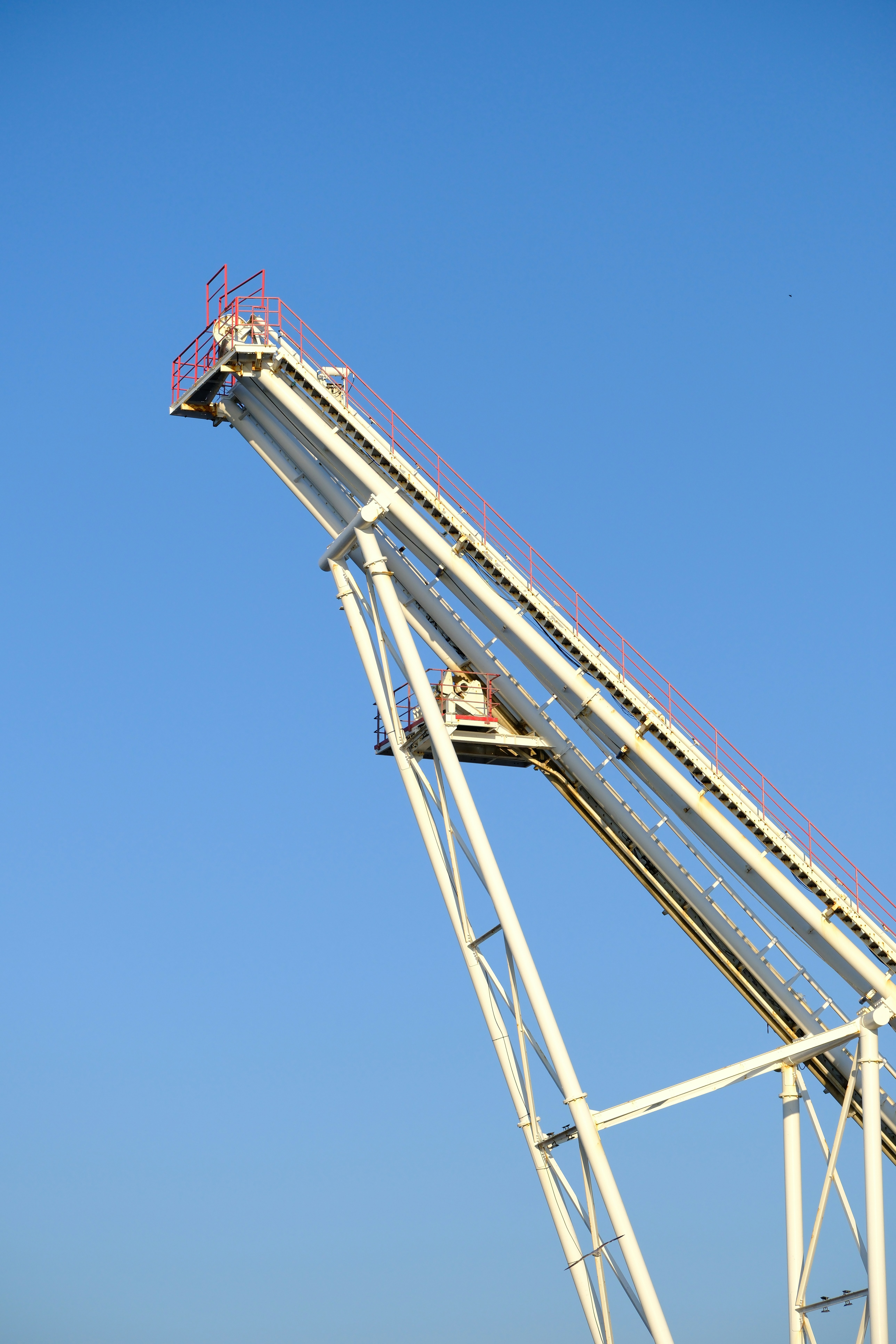 White steel ascent: a crane-like structure slicing the cobalt sky