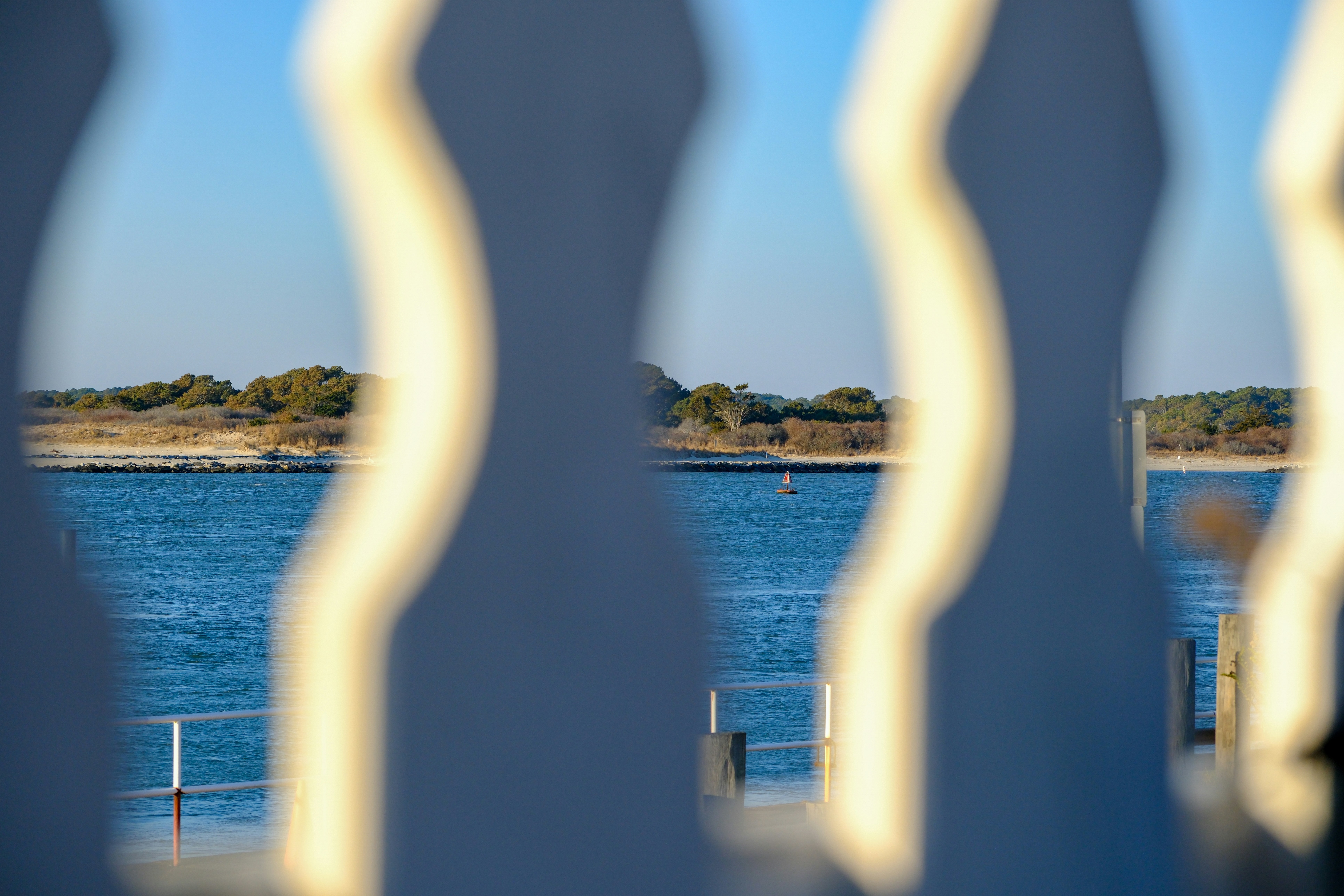 Through the Gate: a sunlit coastline peeks between curving balustrades