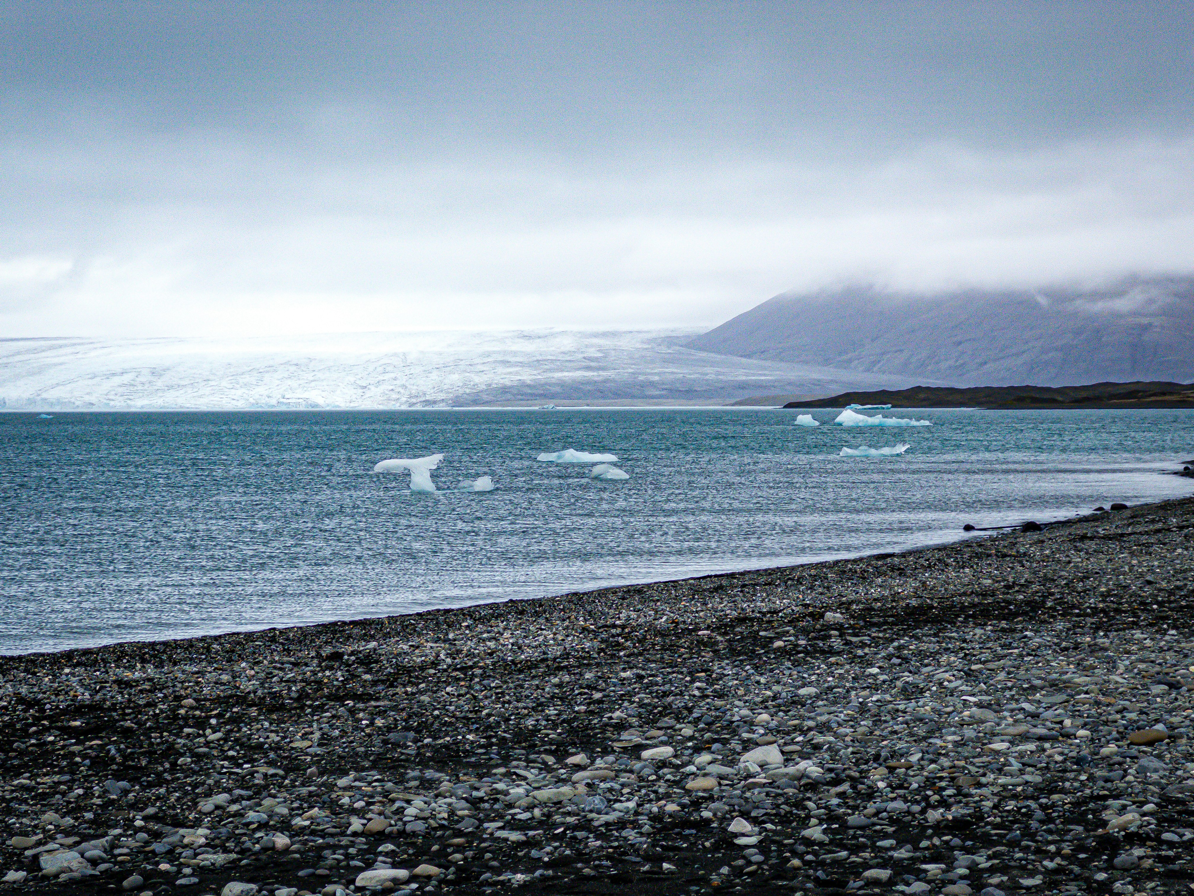 Pebble Beach and Ice-Tinted Horizon Under Cloud Sweep