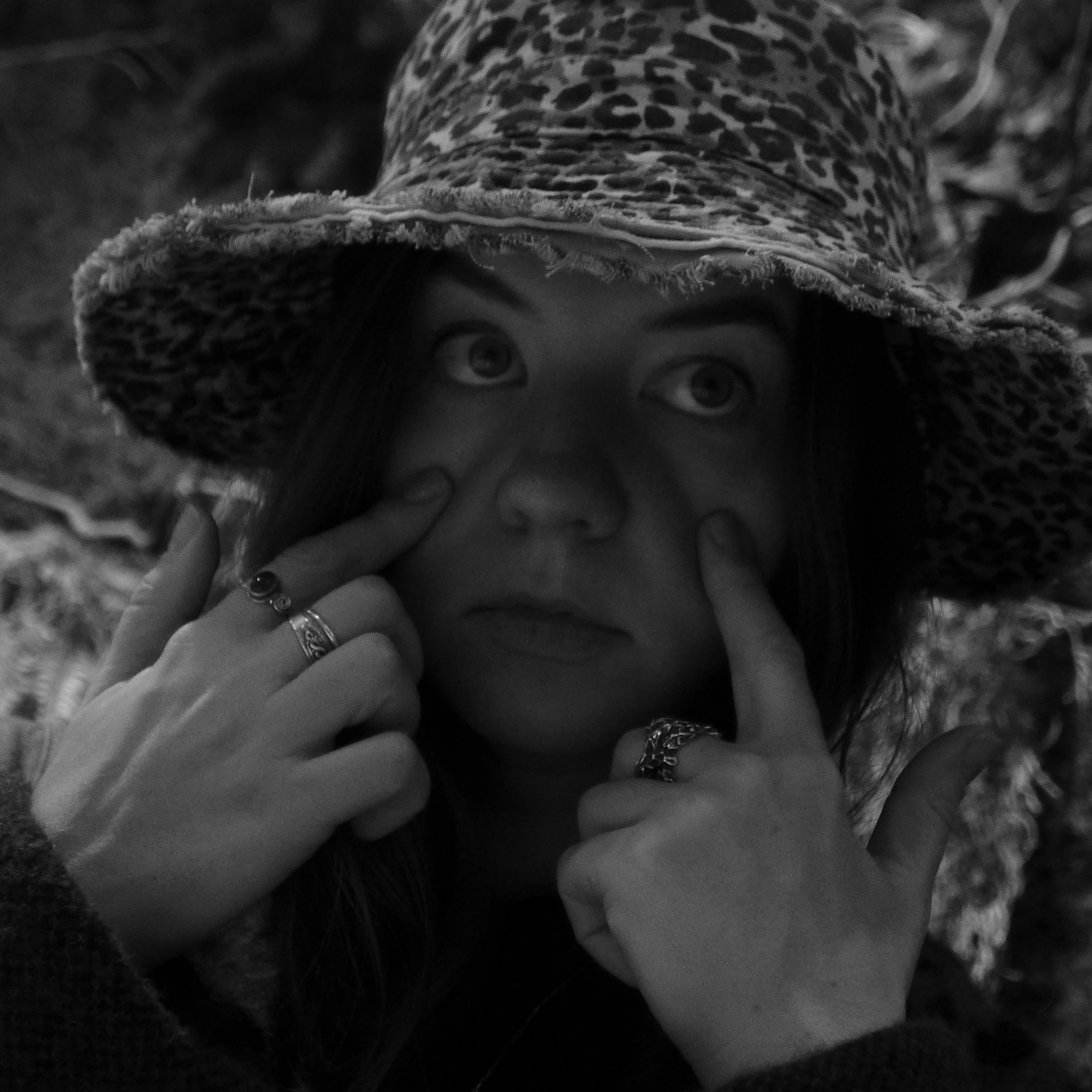 Woman wearing a leopard print hat points at eyes