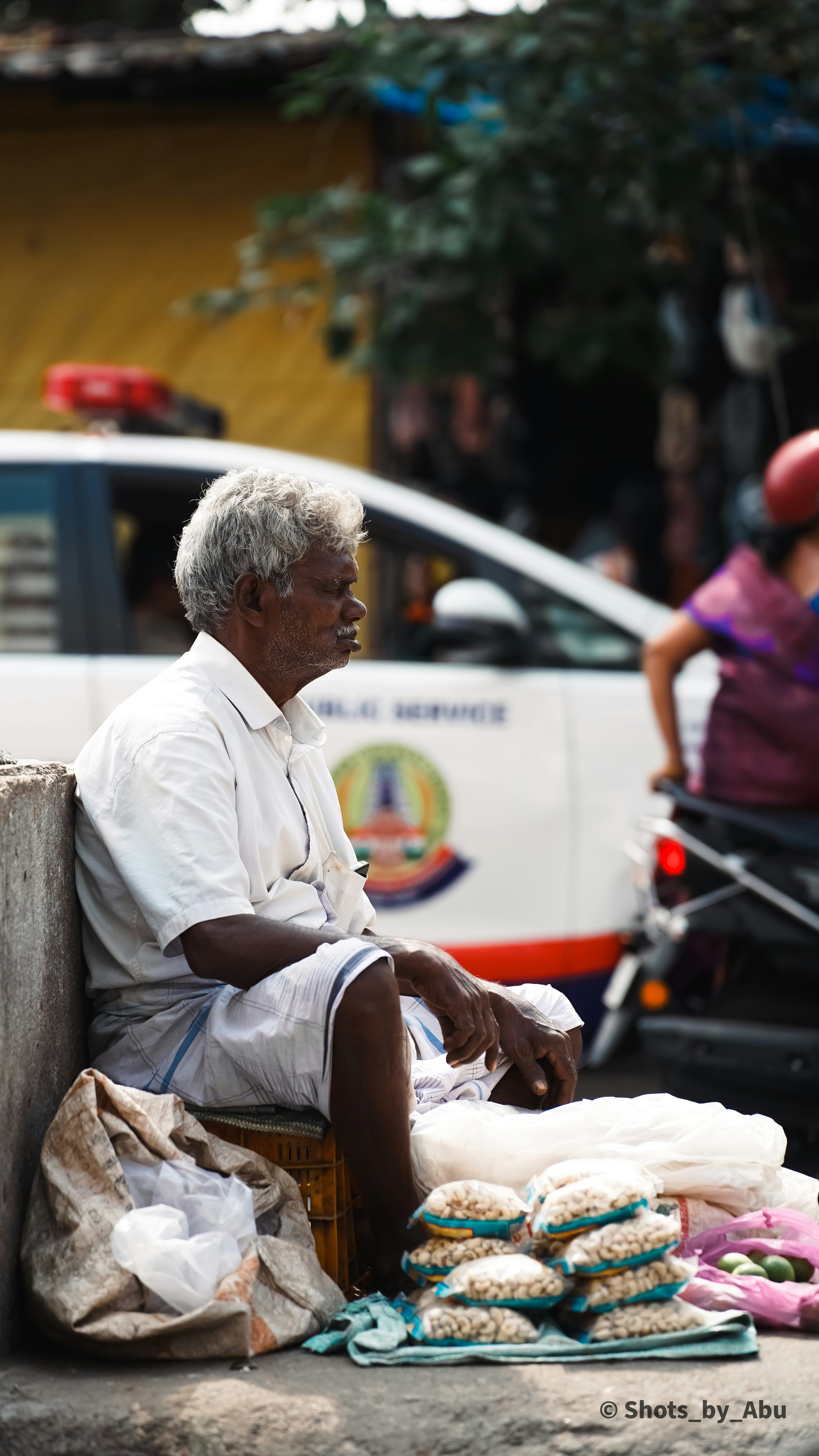 Old Street Vendor with Bags of Popcorn Under a Shaded Balcony