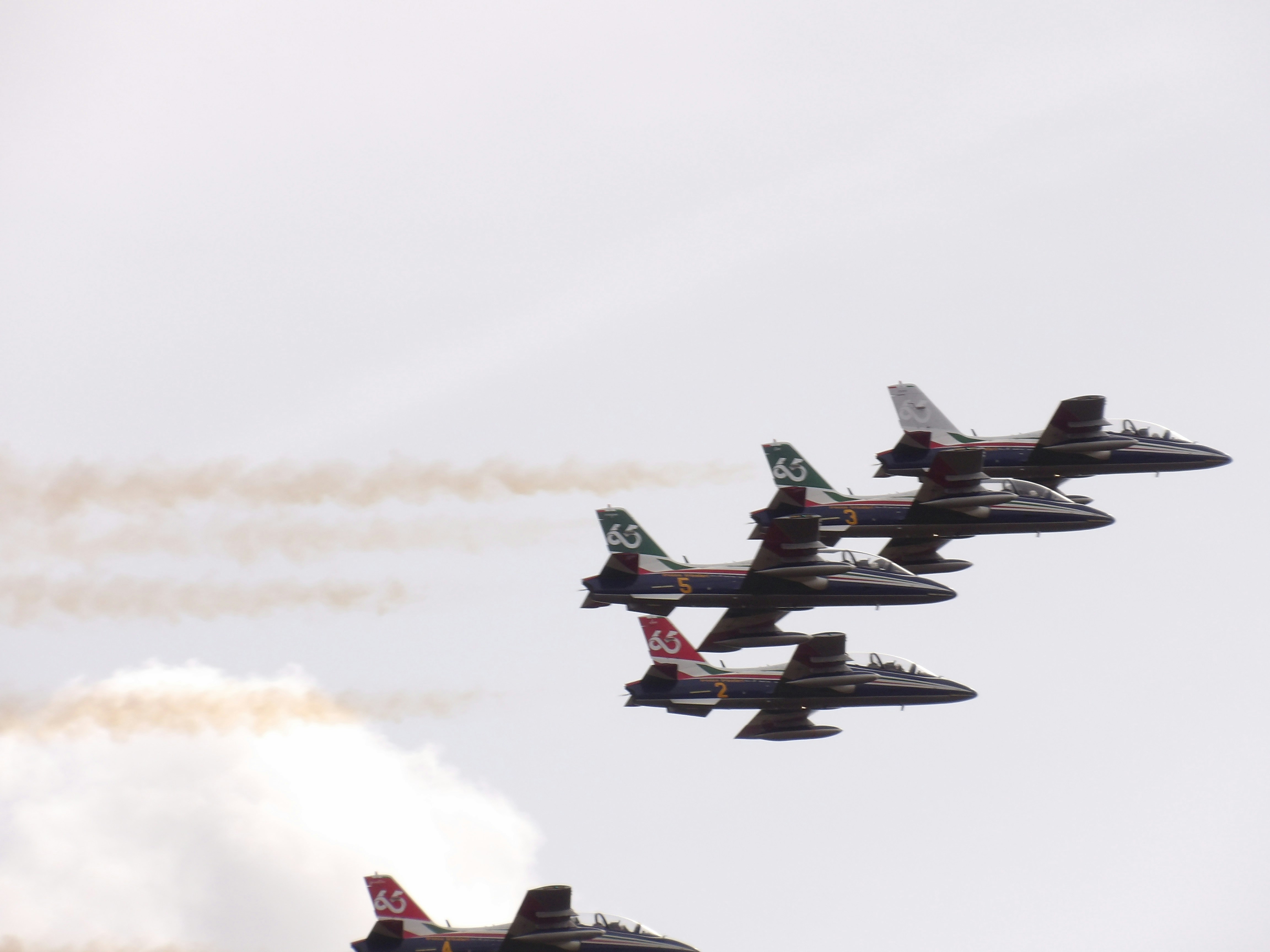Five fighter jets flying in formation with smoke trails.