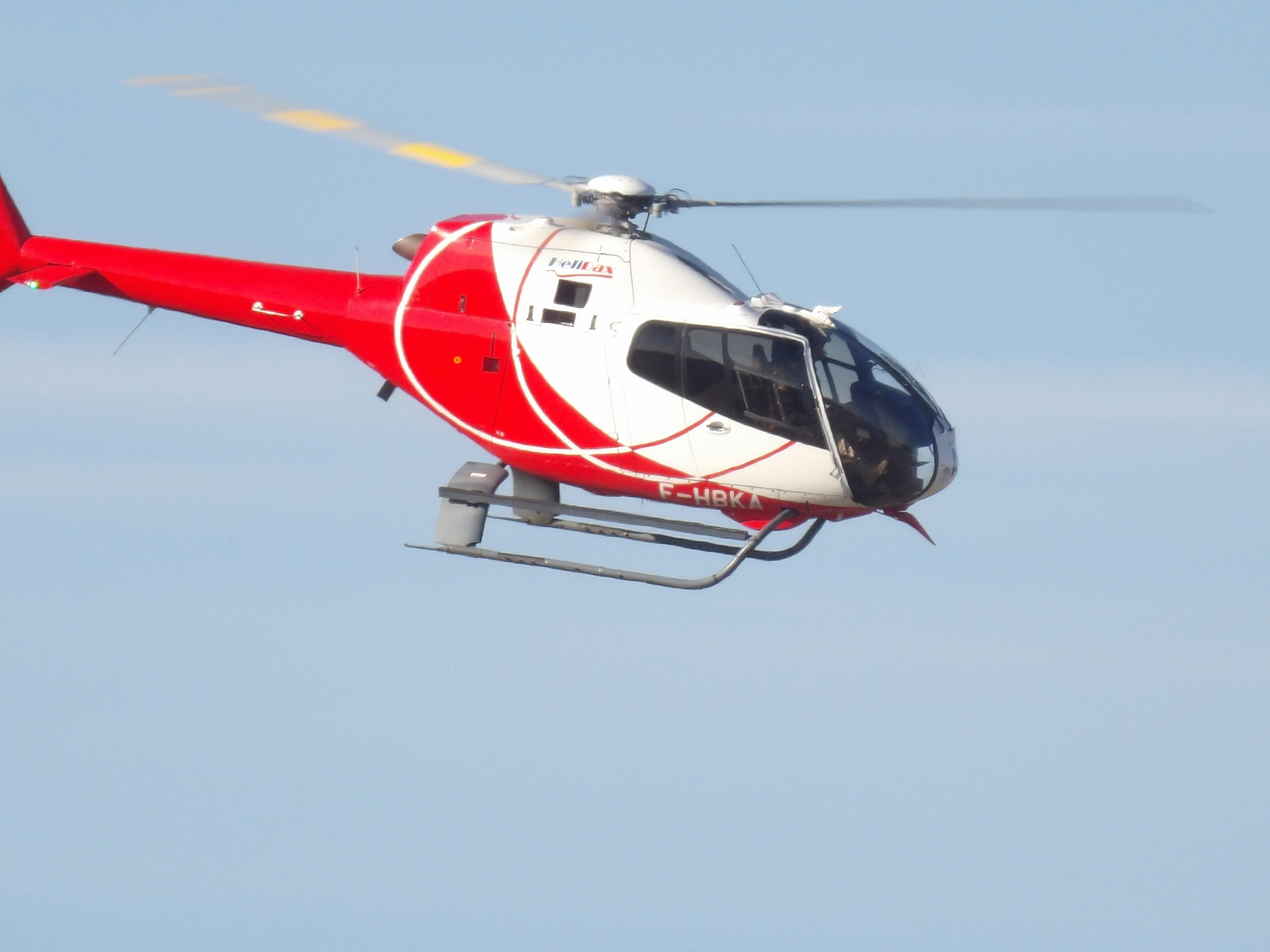 A red and white helicopter flying in the sky.