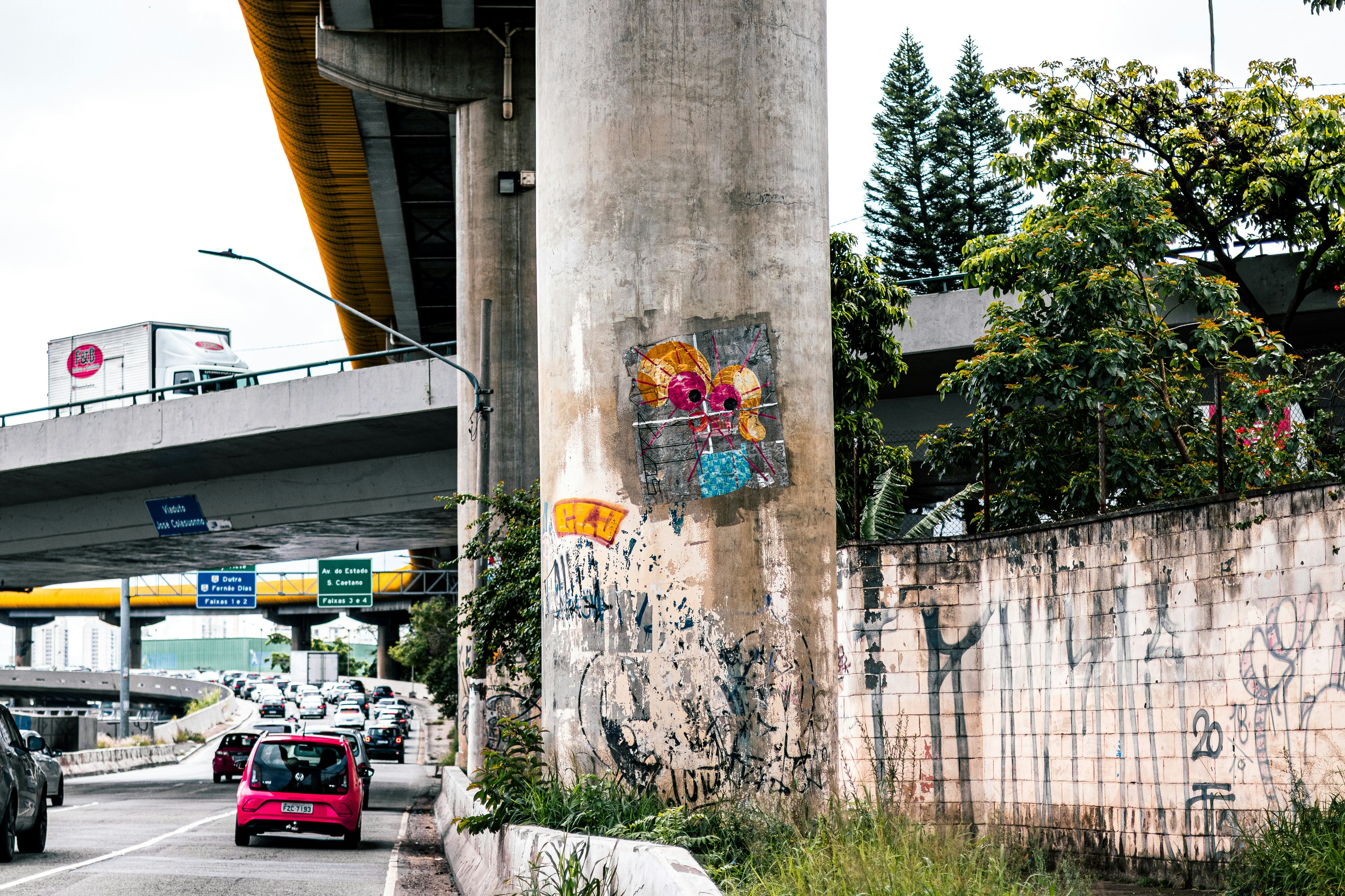 Urban Underpass: Graffiti, Concrete Column, and a Bright Red Mini in Traffic