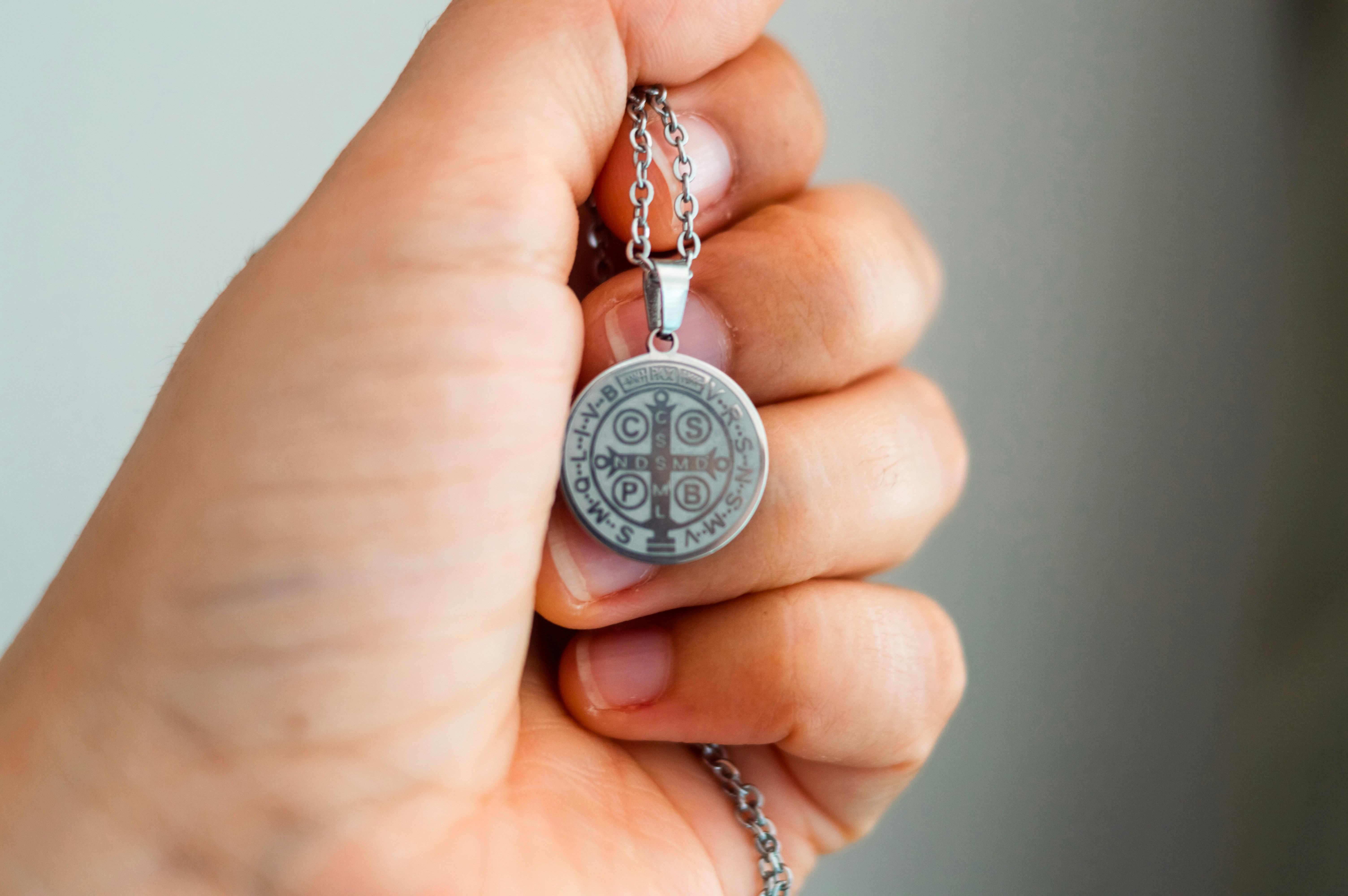Pendant Clasp: A Close-Up of a Metal Token Gripped by Fingers