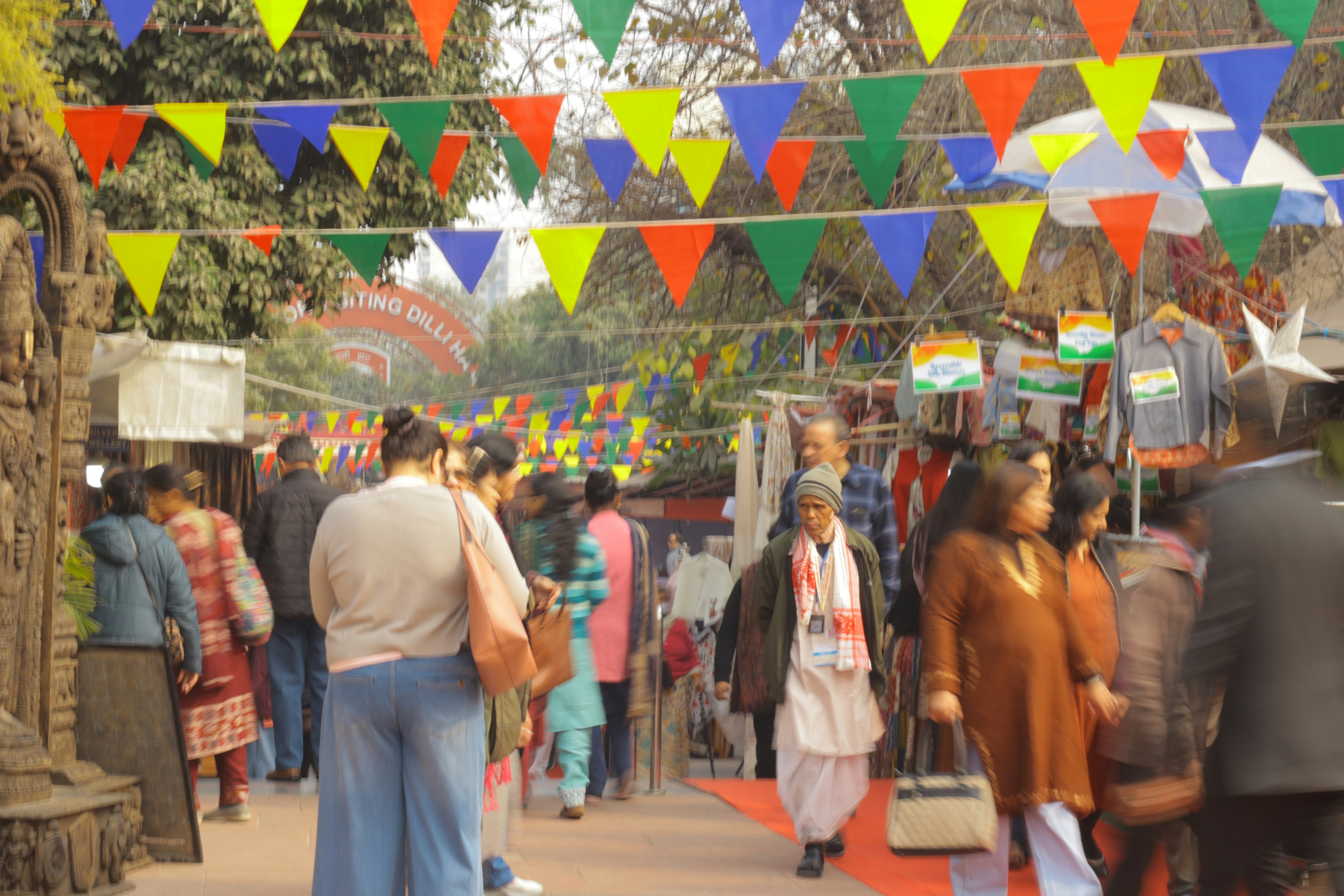view of a busy street in dilli haat in central Delhi with an old man in traditional indian attire walking towards camera