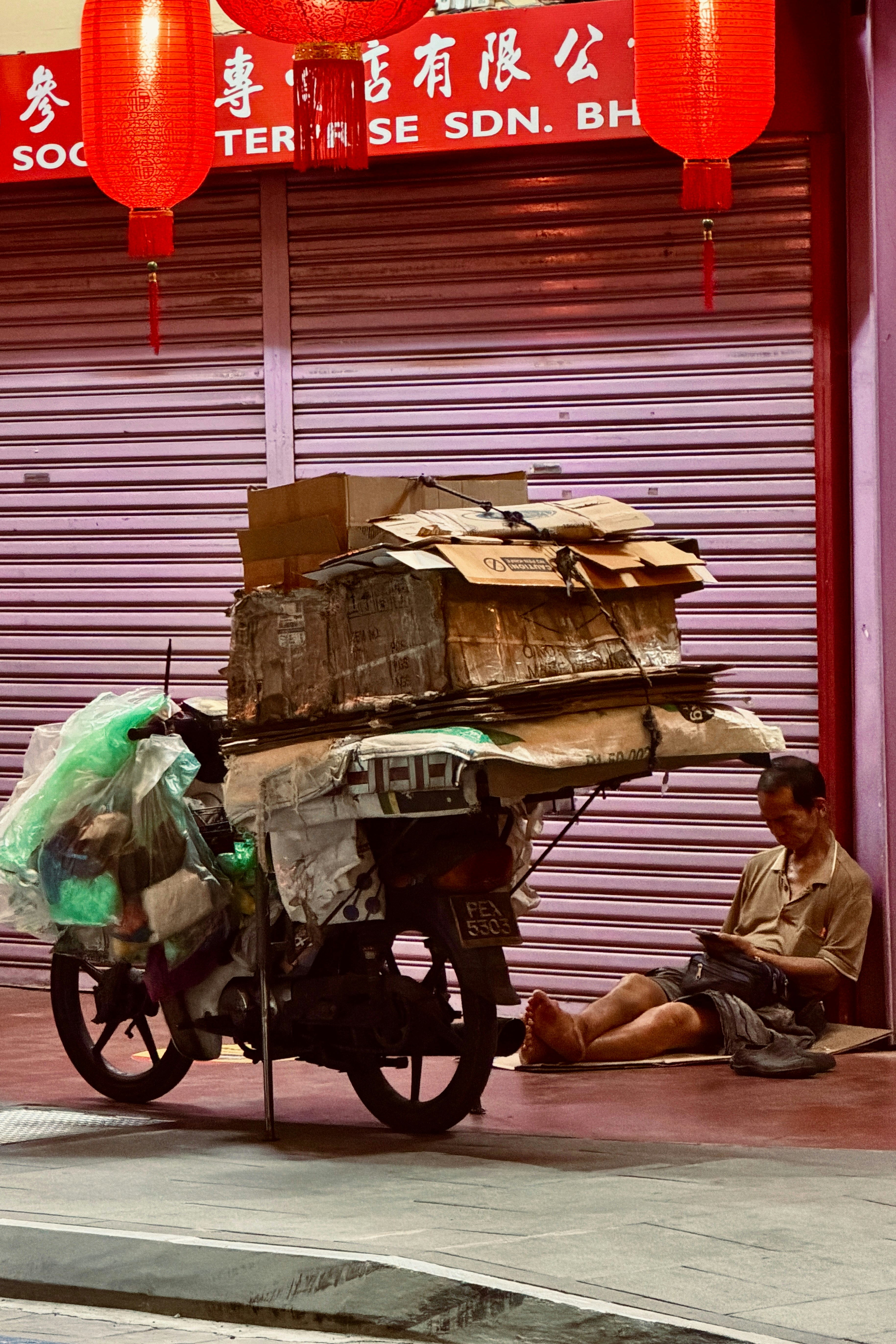 Cardboard Caravan: Drifter’s Load Beneath a Red Lantern
