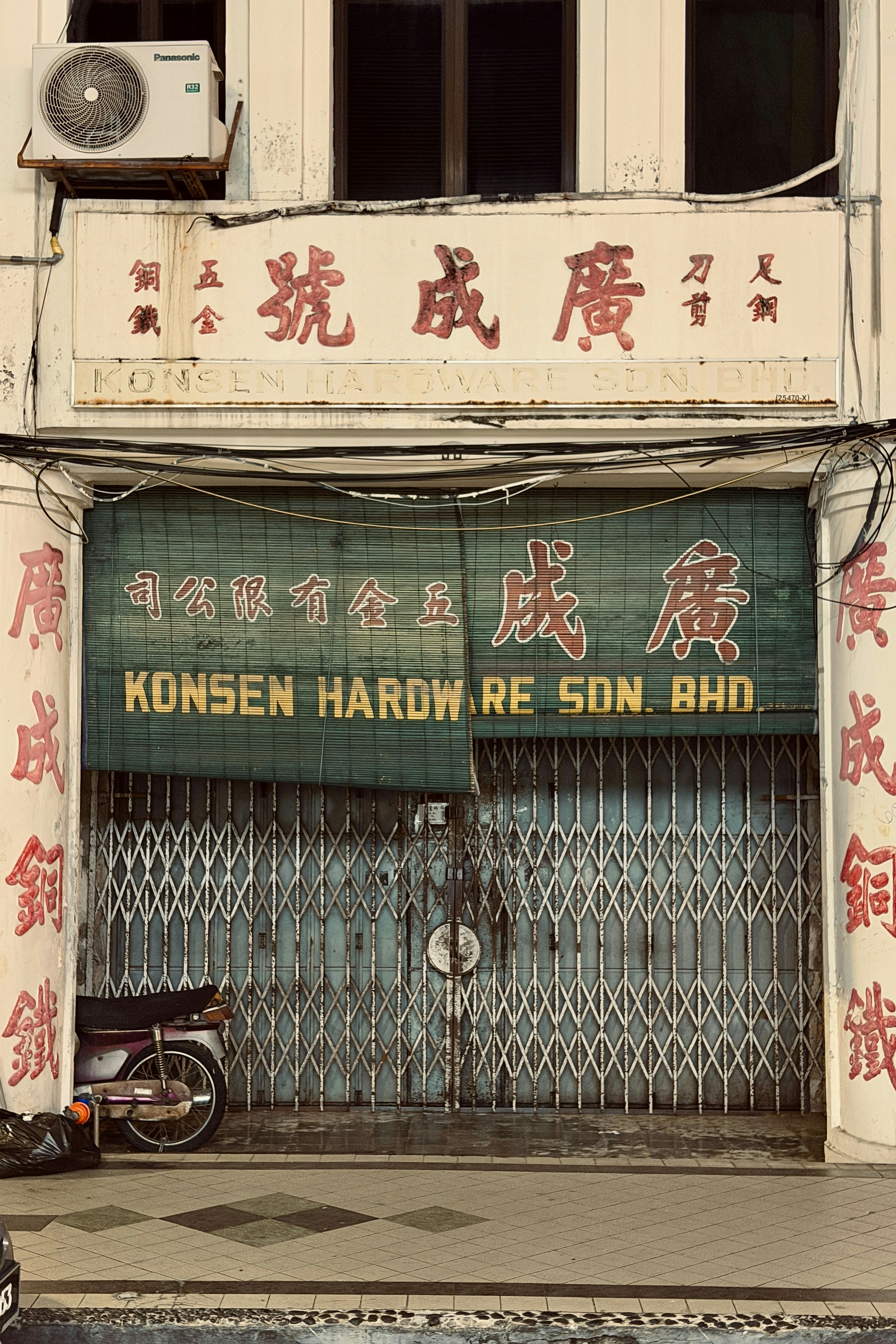 Closed Gate of a Hardware Shop: Weathered Facade, Red Chinese Characters and A Hidden Bicycle
