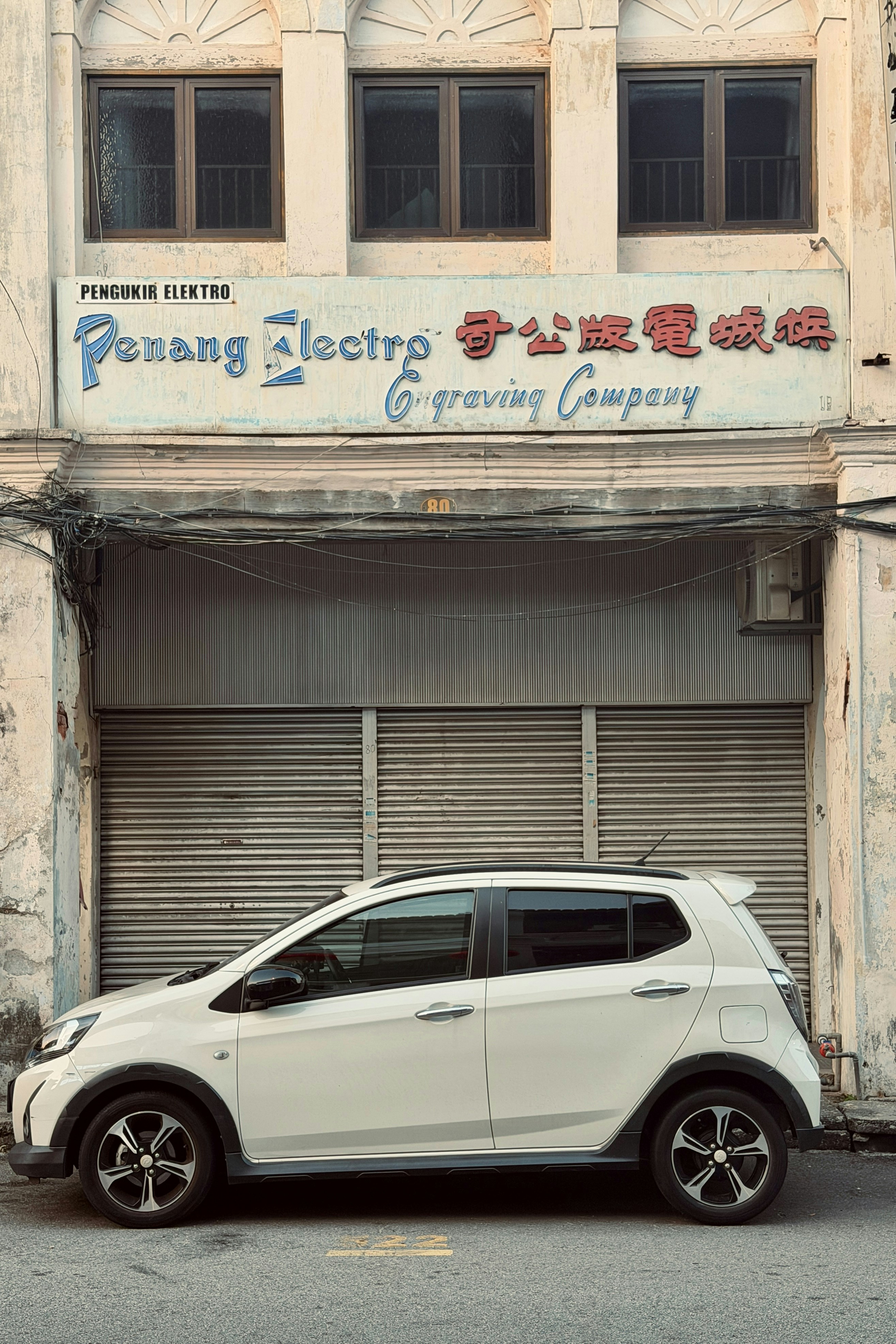 White compact car parked before a weathered storefront