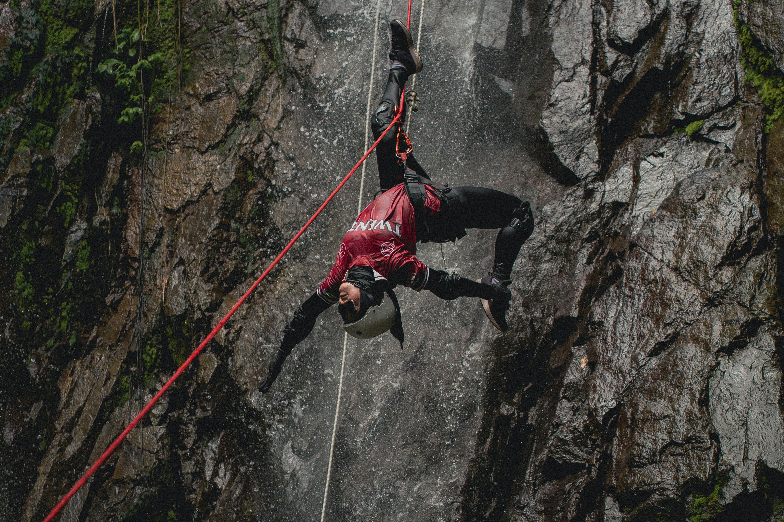 Climber in Freefall: A Red-Sashed Ascent on a Granite Face