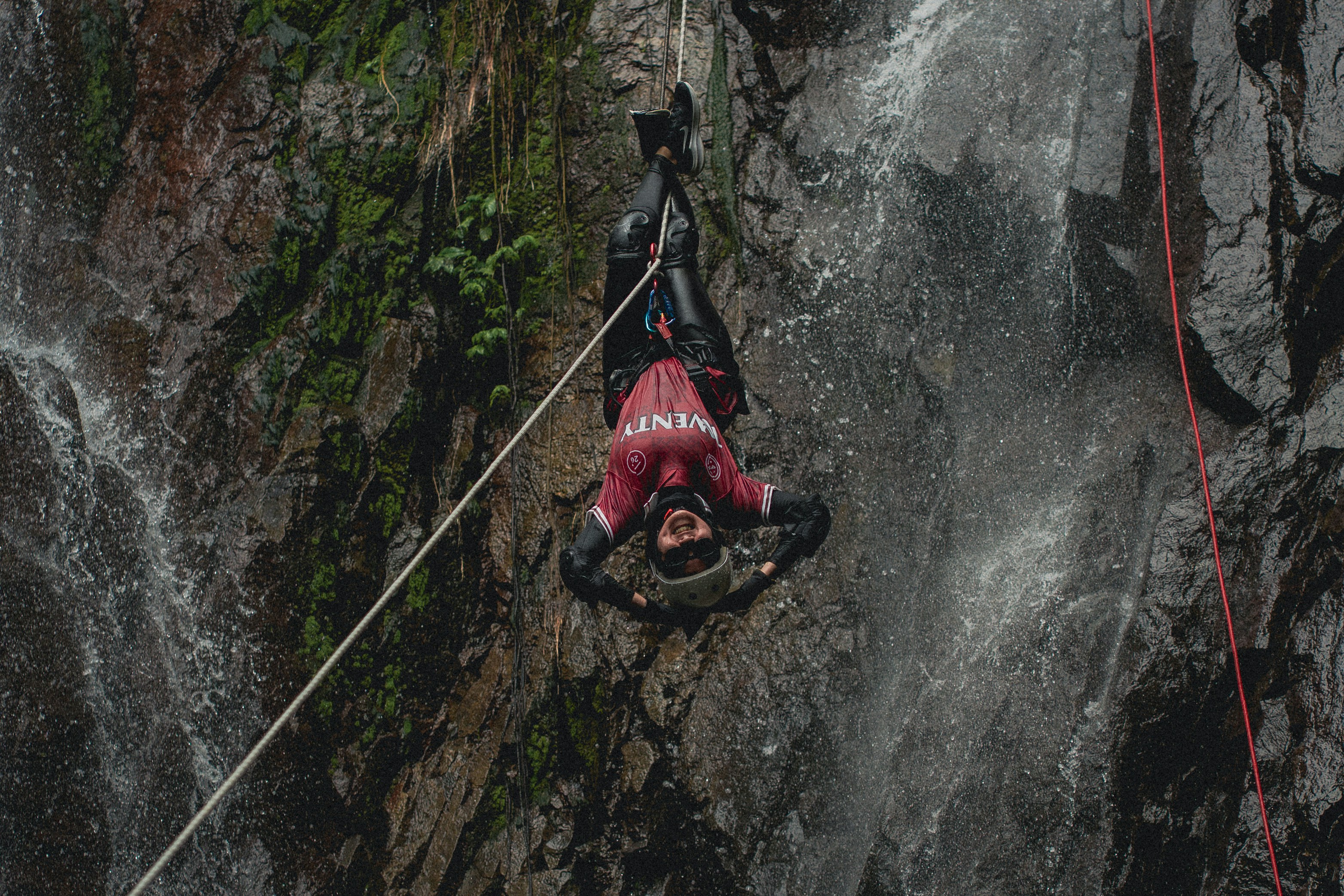 Aerial Climber suspended mid-ascent against rugged cliff