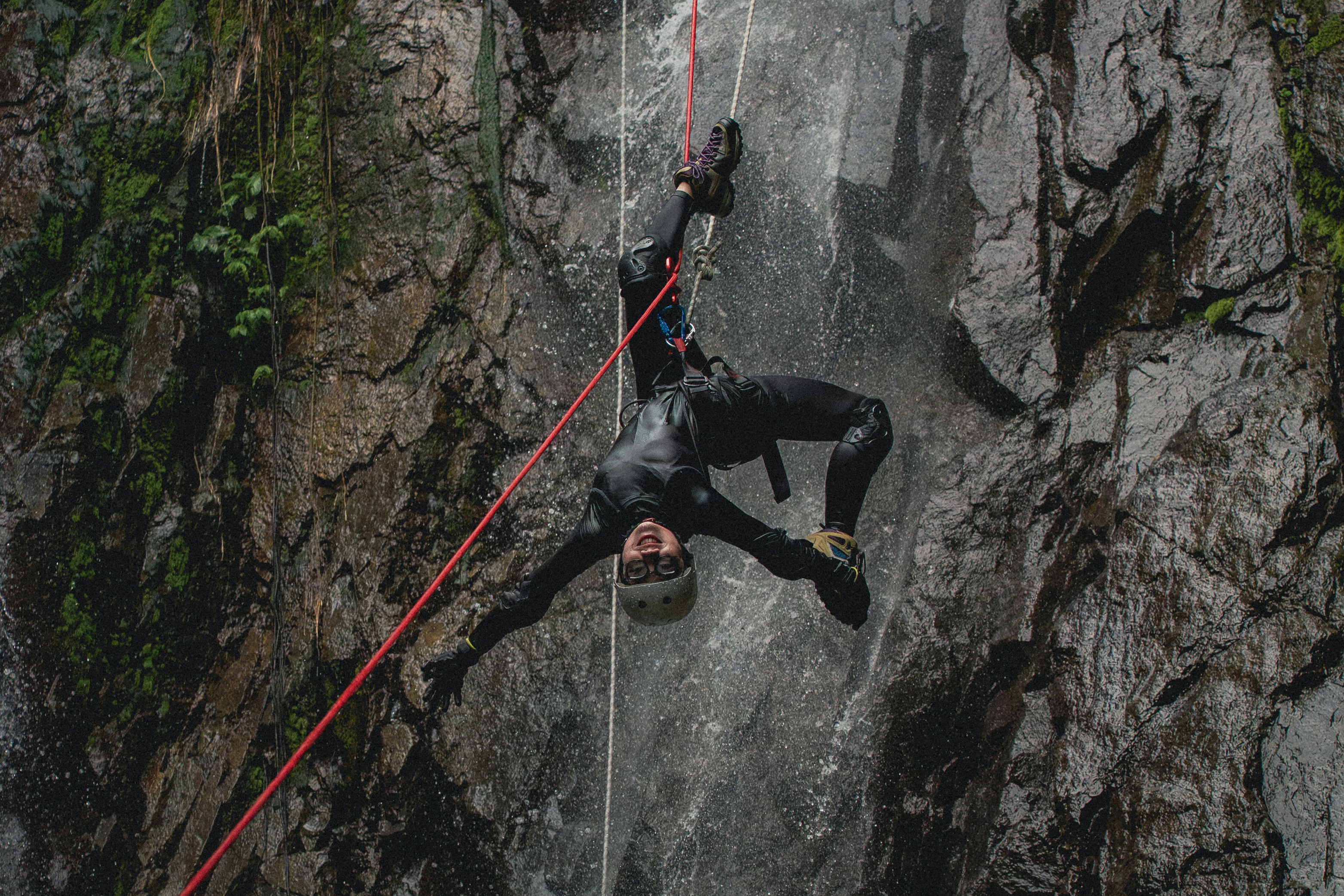 Cascading Descent: A Climber Anchored to a Slick Cliff