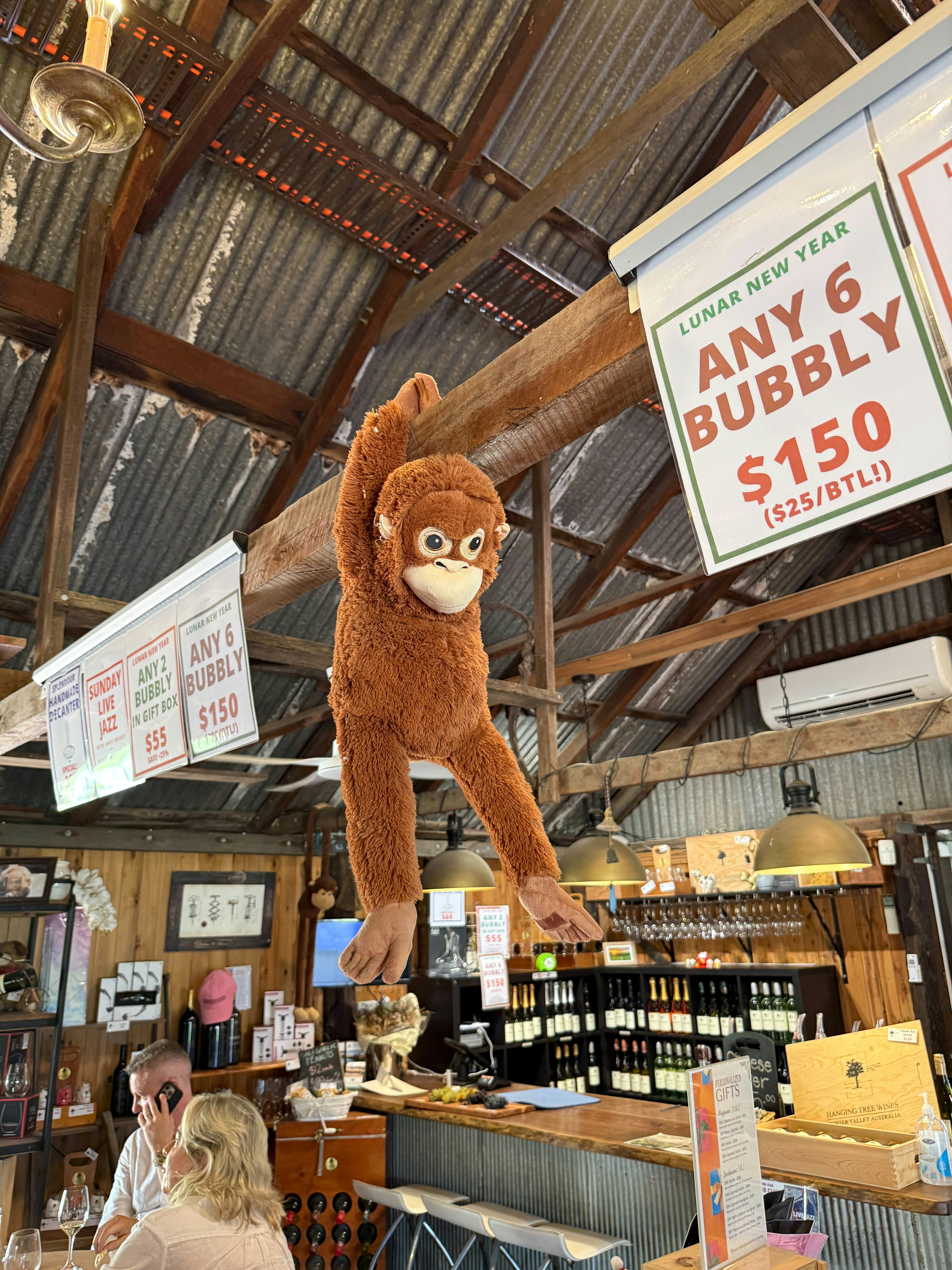 Swinging Mystery: A Plush Primate Floats Above a Rustic Tasting Room