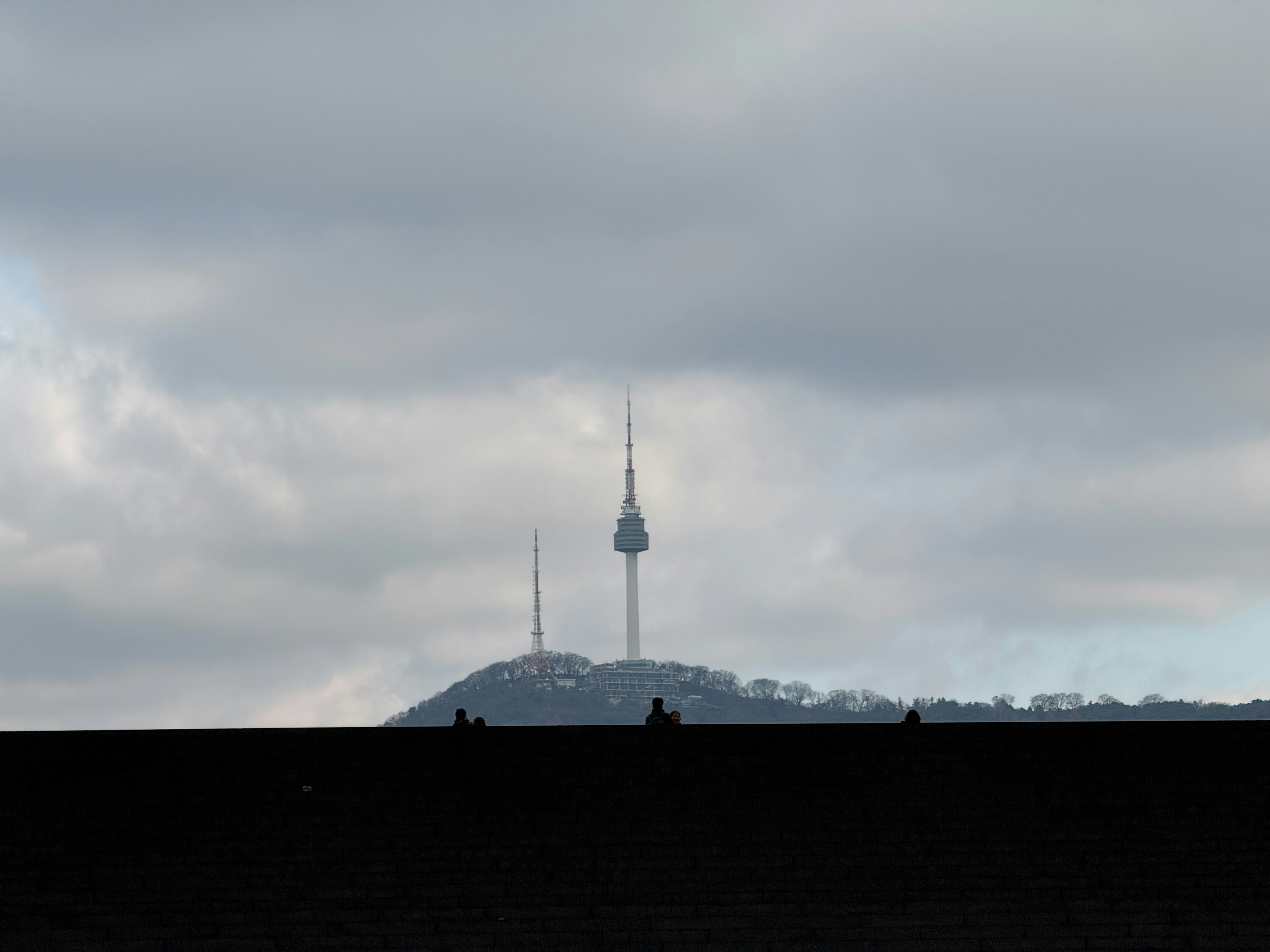 Silhouette Above the City: A Towered Crest Against Clouded Sky