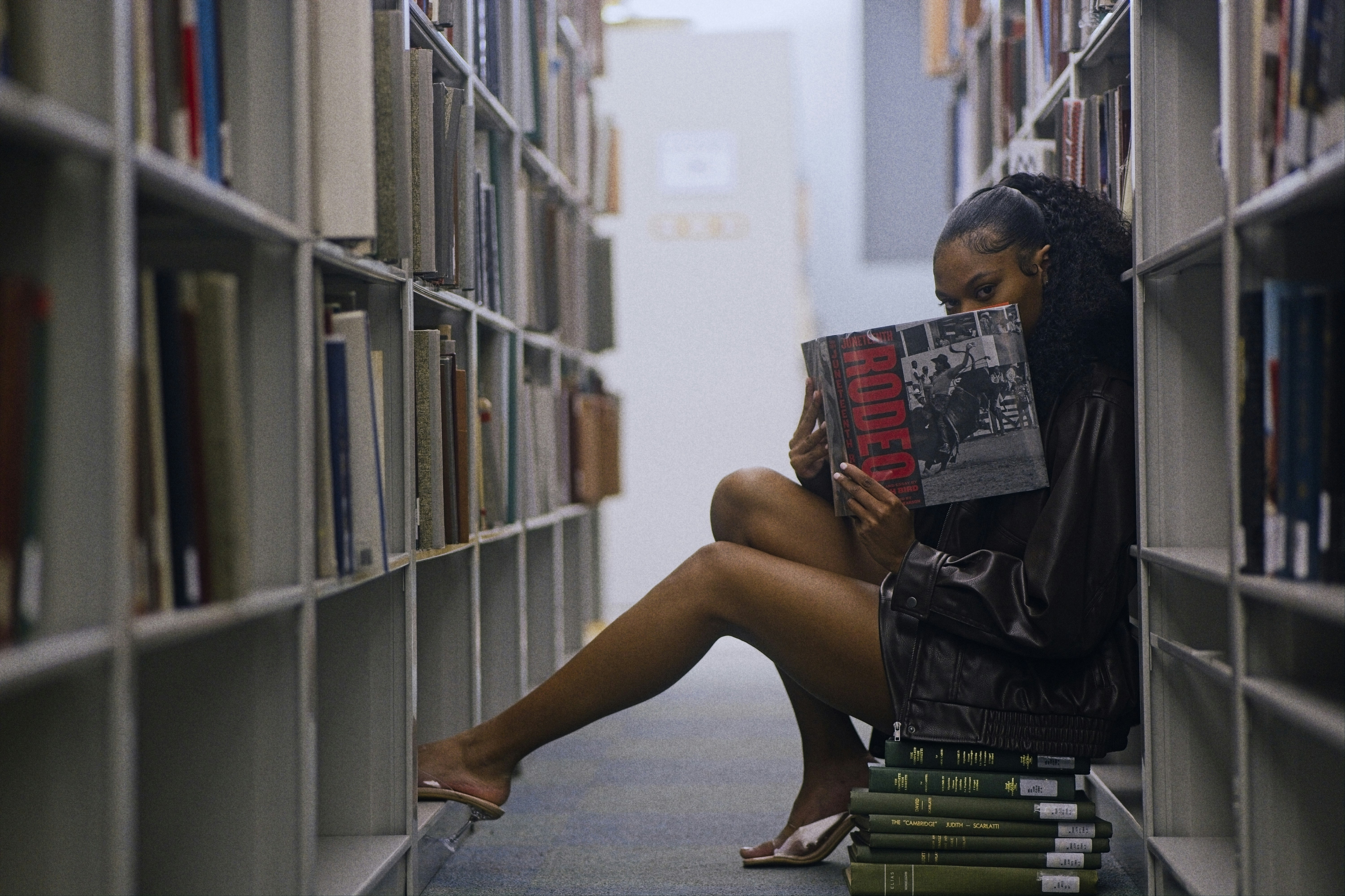 Quiet Librarian: A Reader Amid Stacked Moss Green Volumes
