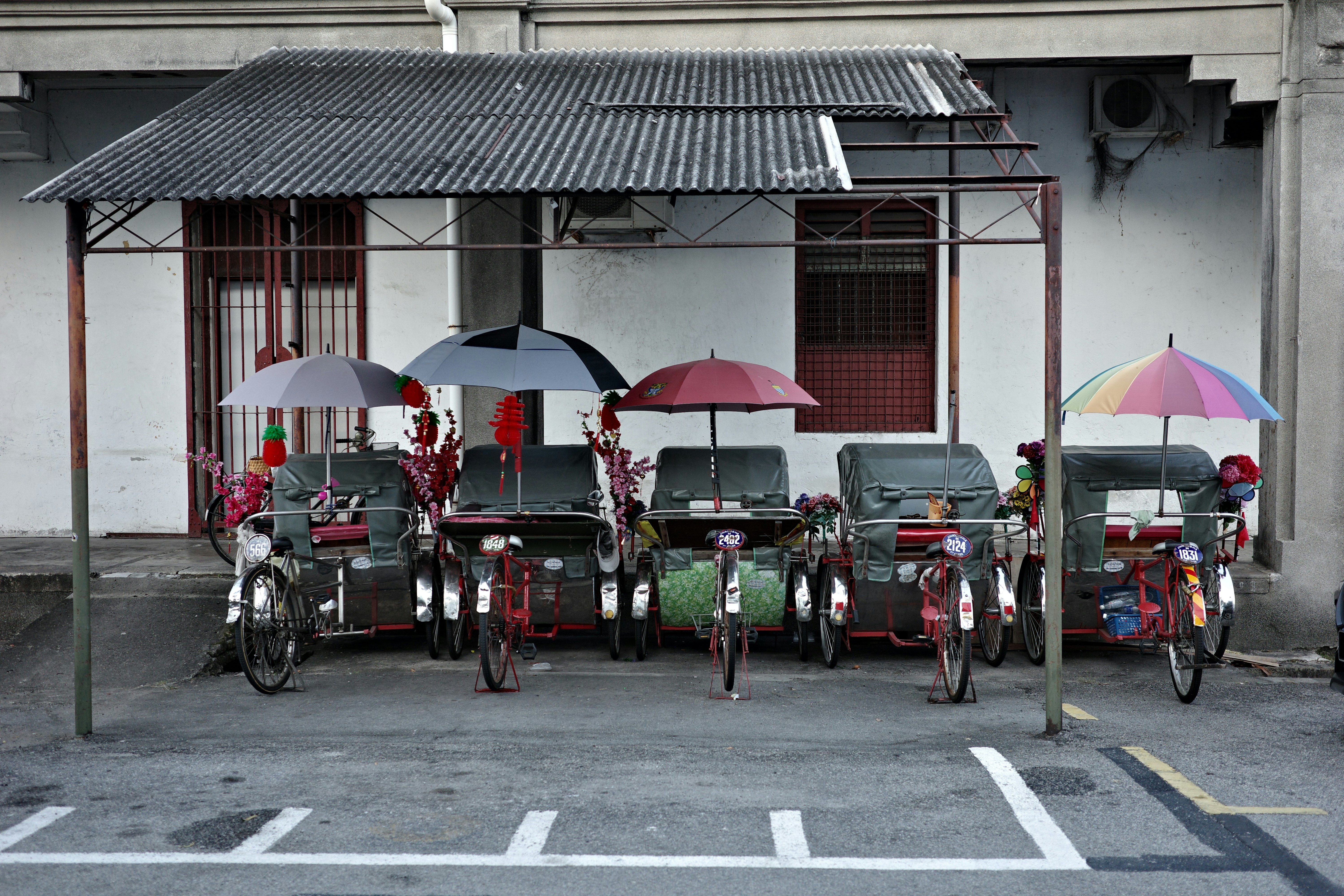 Row of Colorful Umbrella-Topped Pedicabs in a Quiet Courtyard