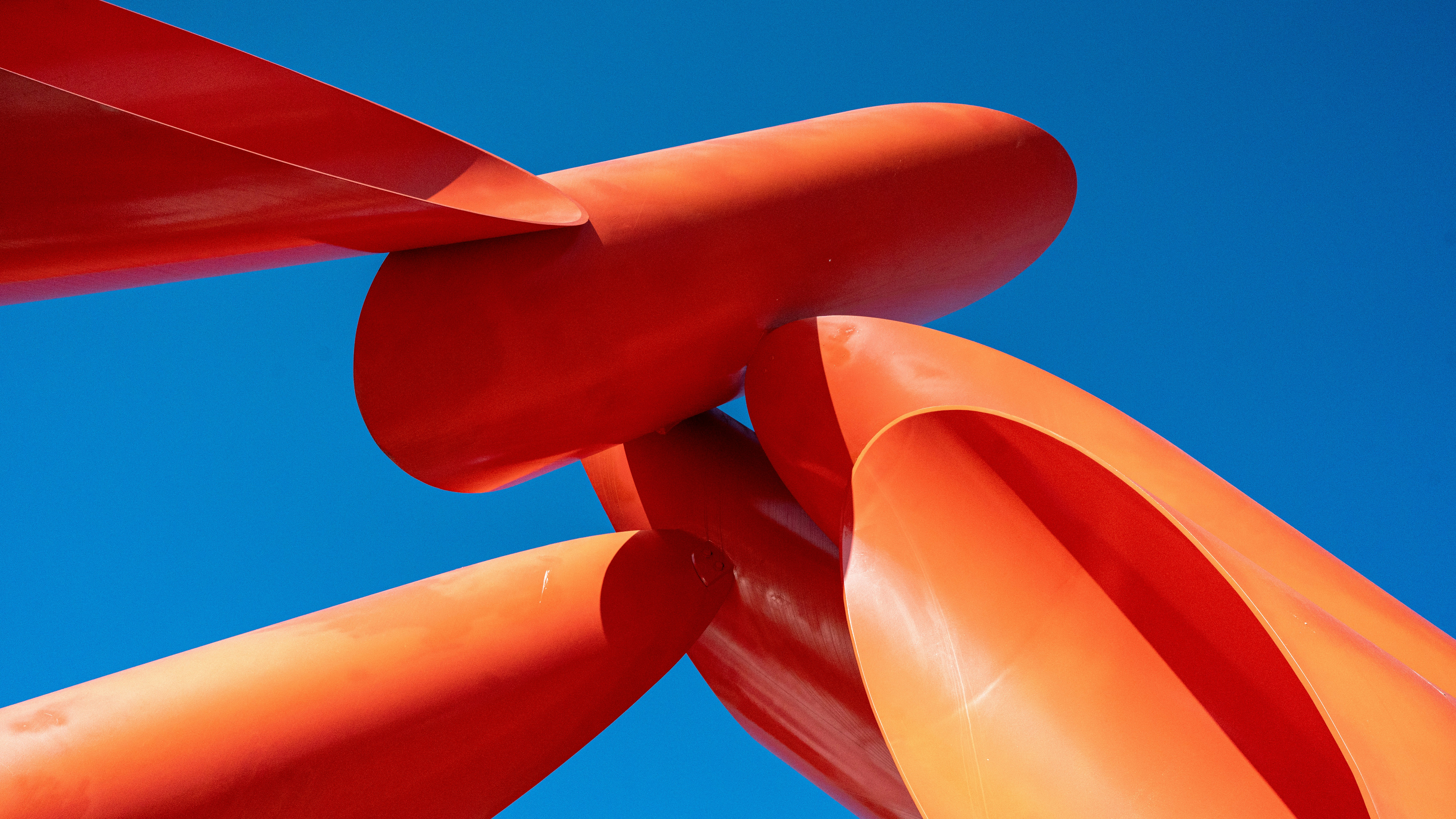 Red Abstract: Interlocking Orange sculptures Against a Clear Blue Sky