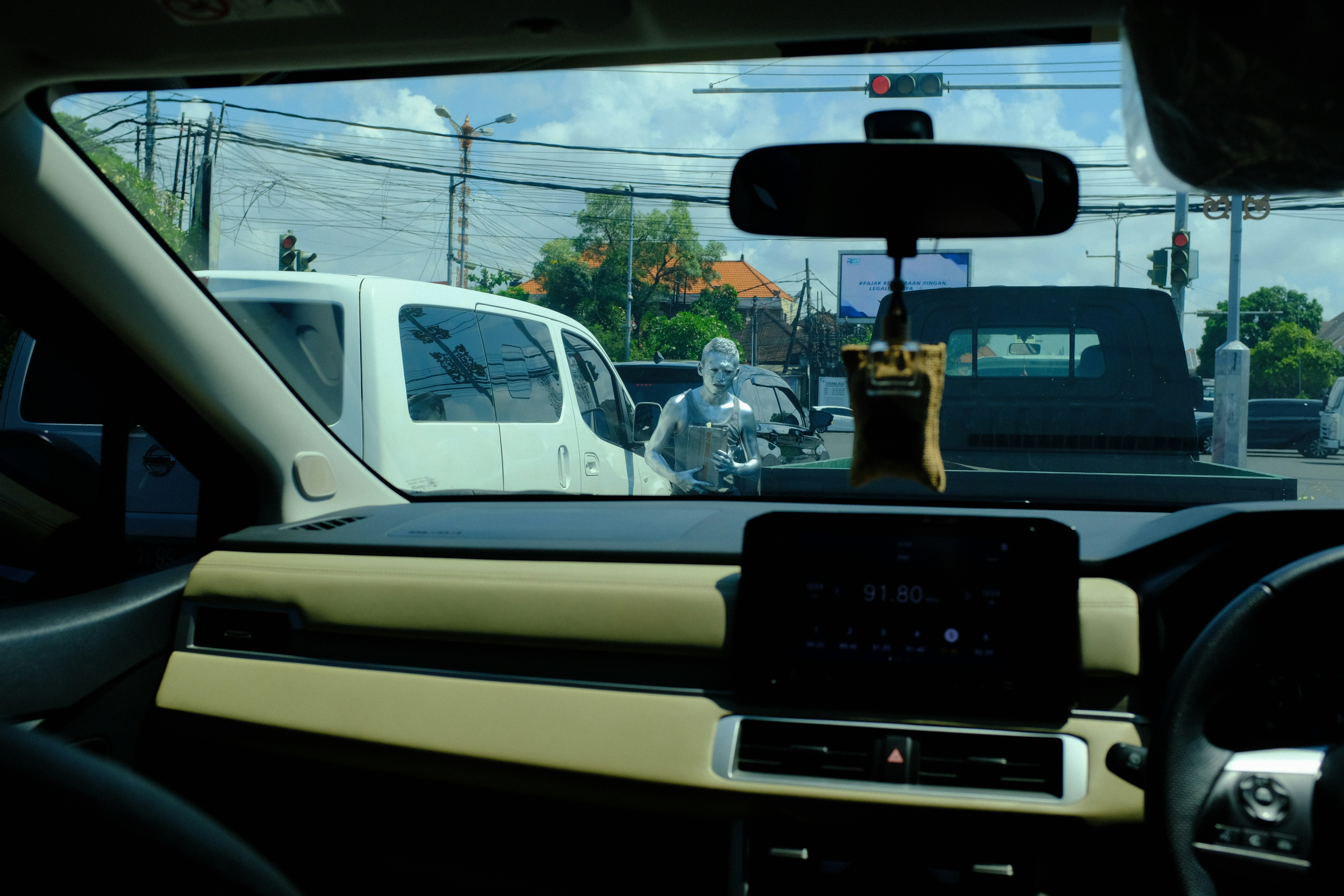 Street Scene Through a Car Windshield: Front Console Framed by Urban Activity