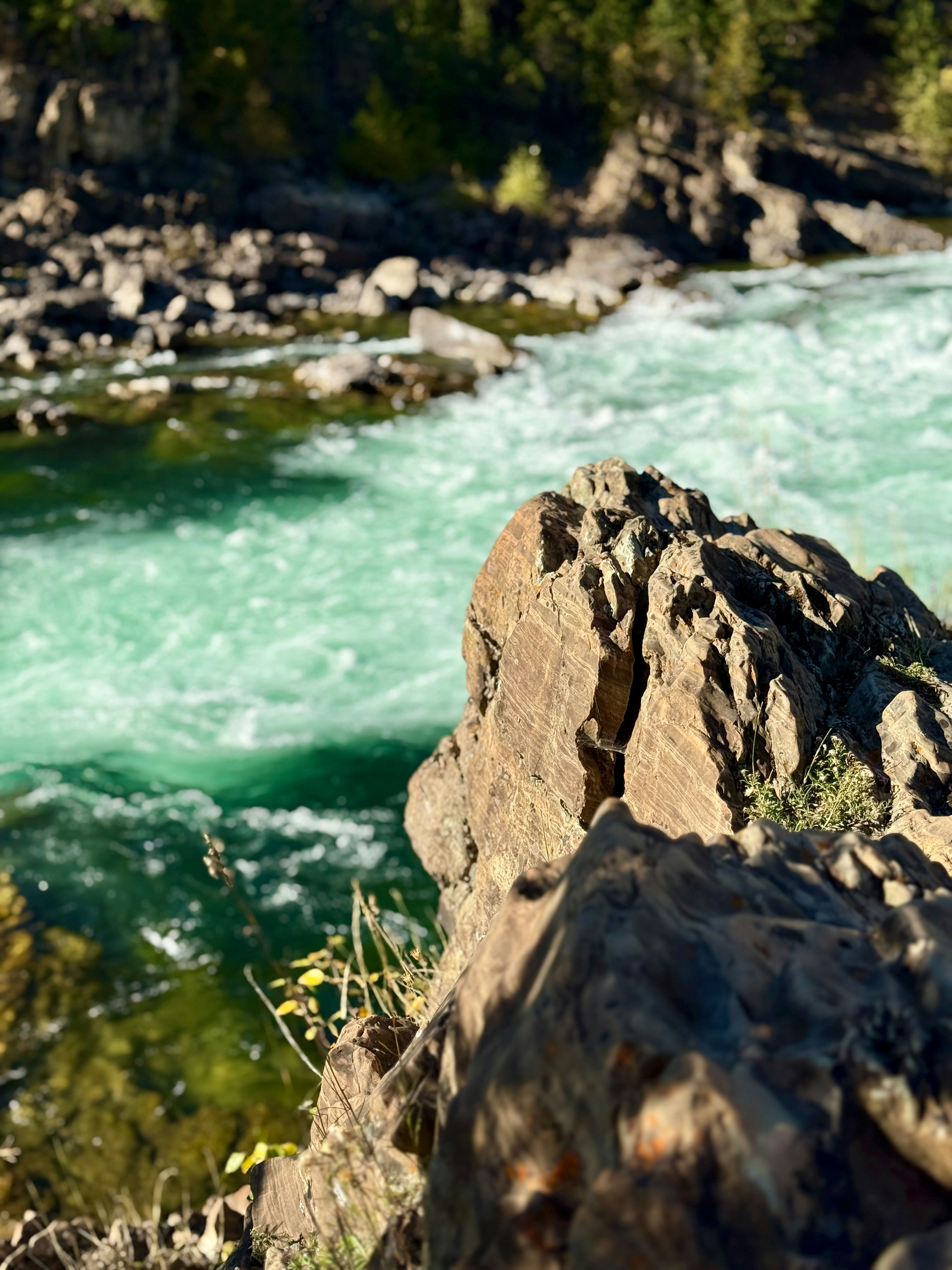 Jagged rock foreground overlooking a turquoise mountain river