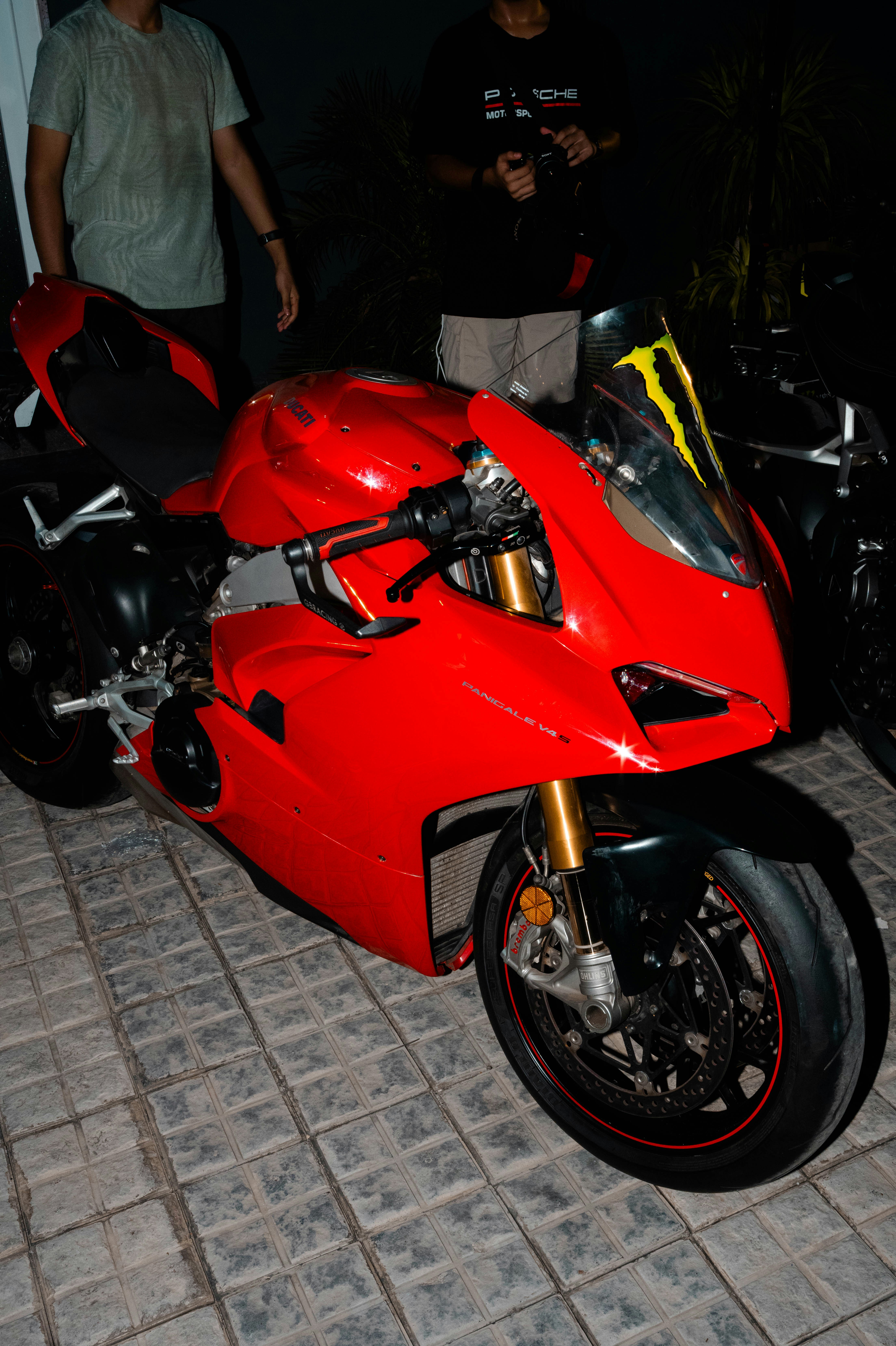 A bright red sport motorcycle parked on a tiled surface.