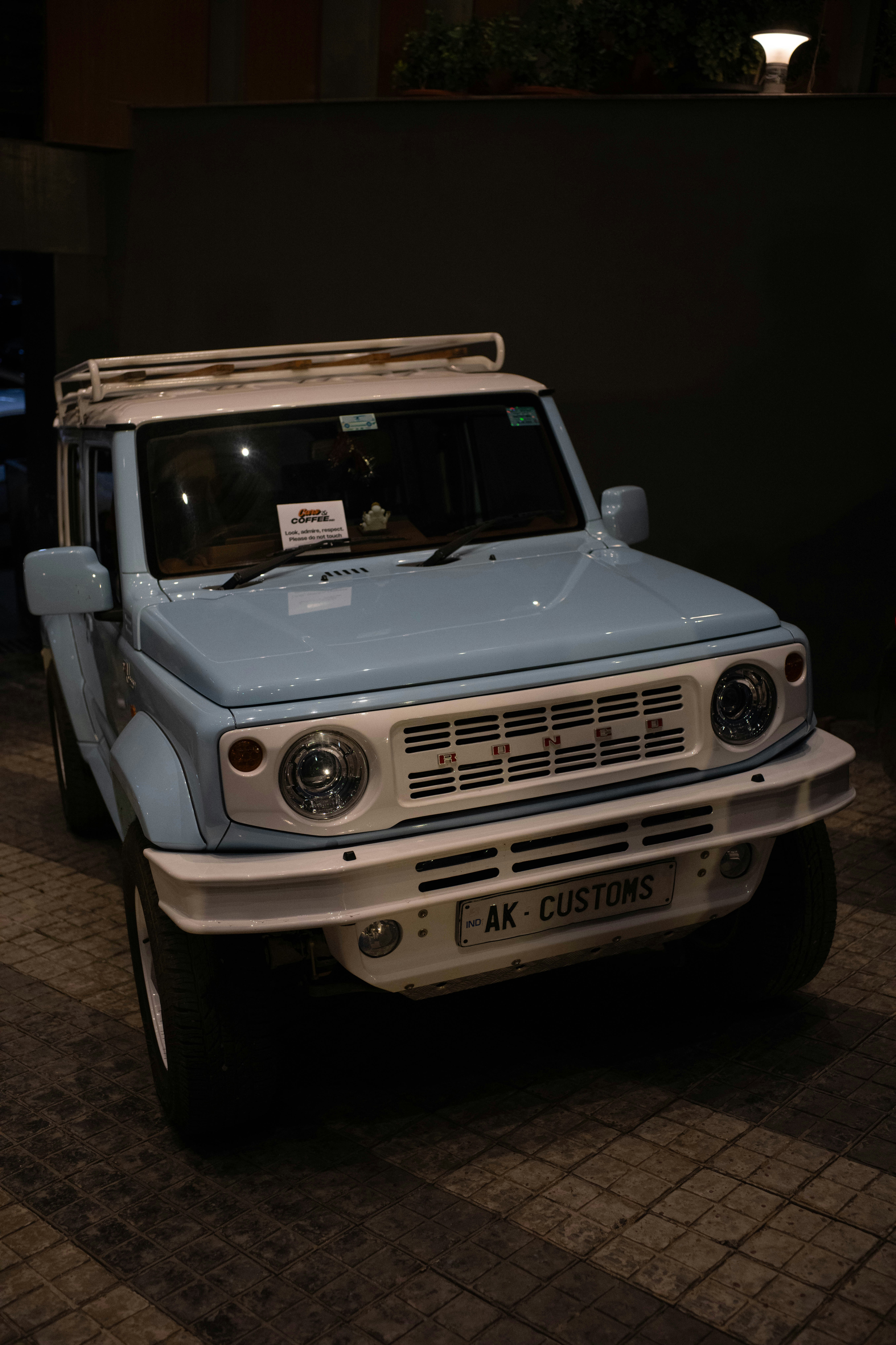 Light blue vintage suv with roof rack parked.