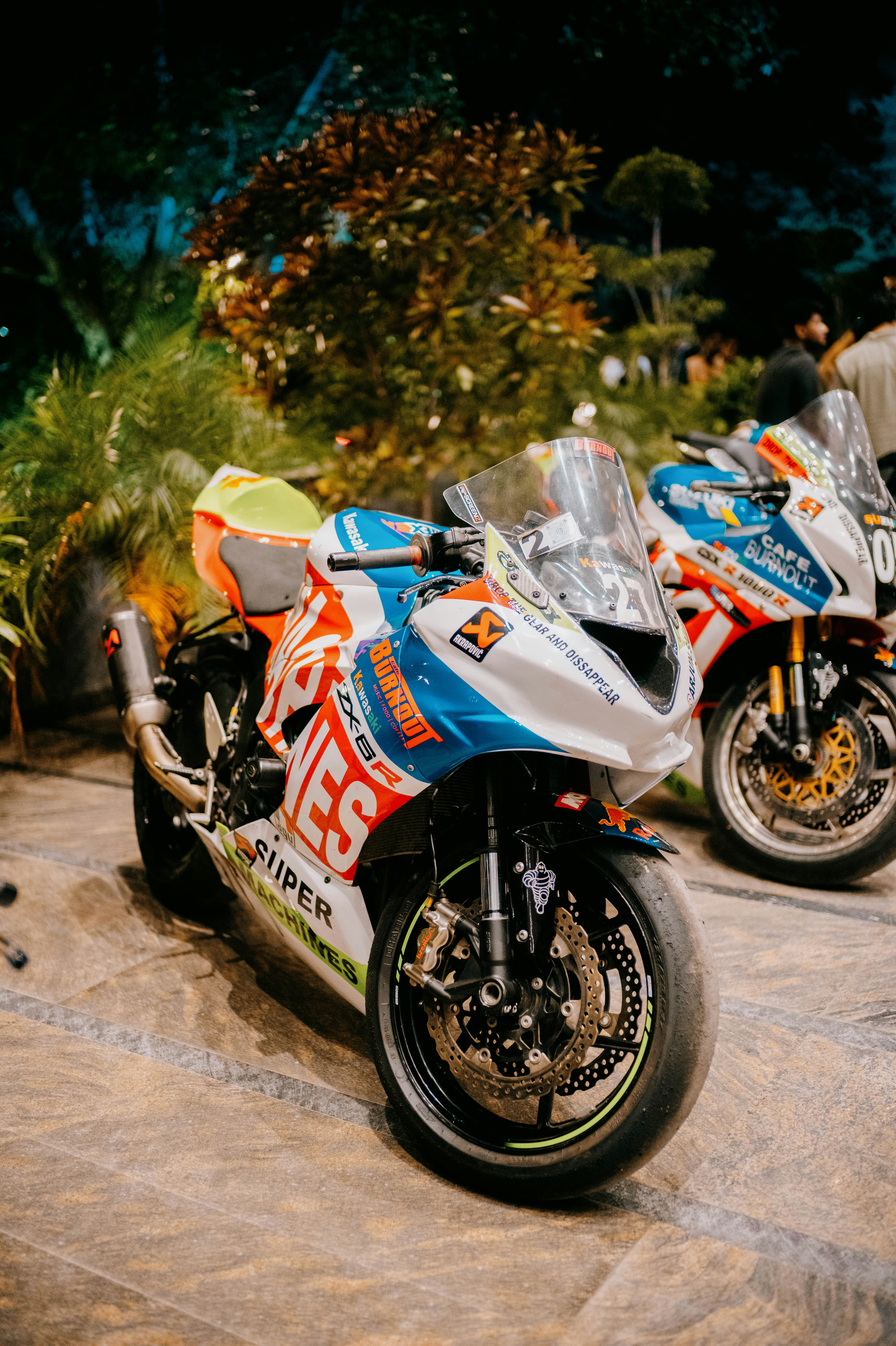Two colorful sport motorcycles parked outdoors.
