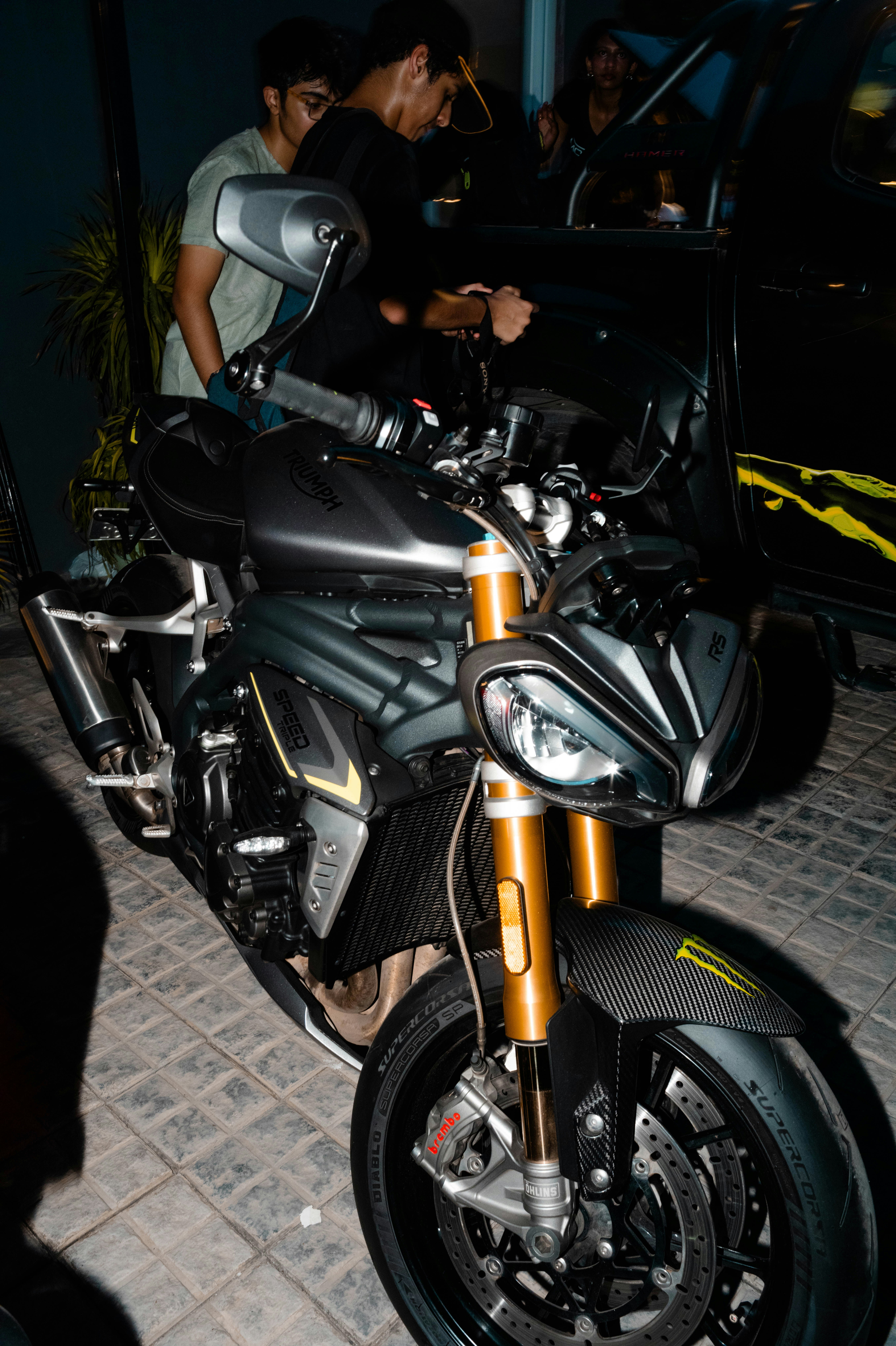 A dark grey motorcycle parked on a tiled surface.