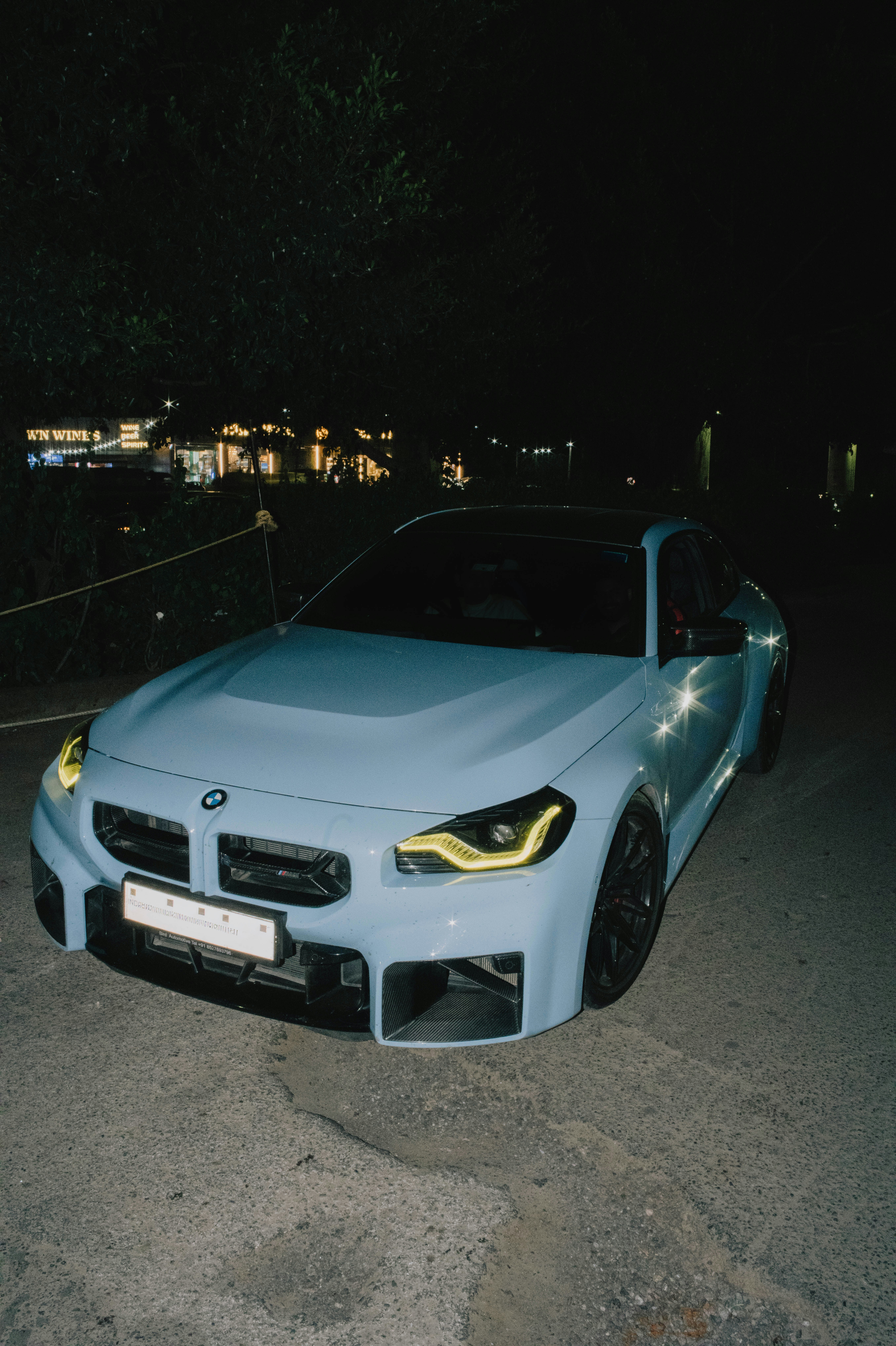 A light blue BMW m2 parked at night.