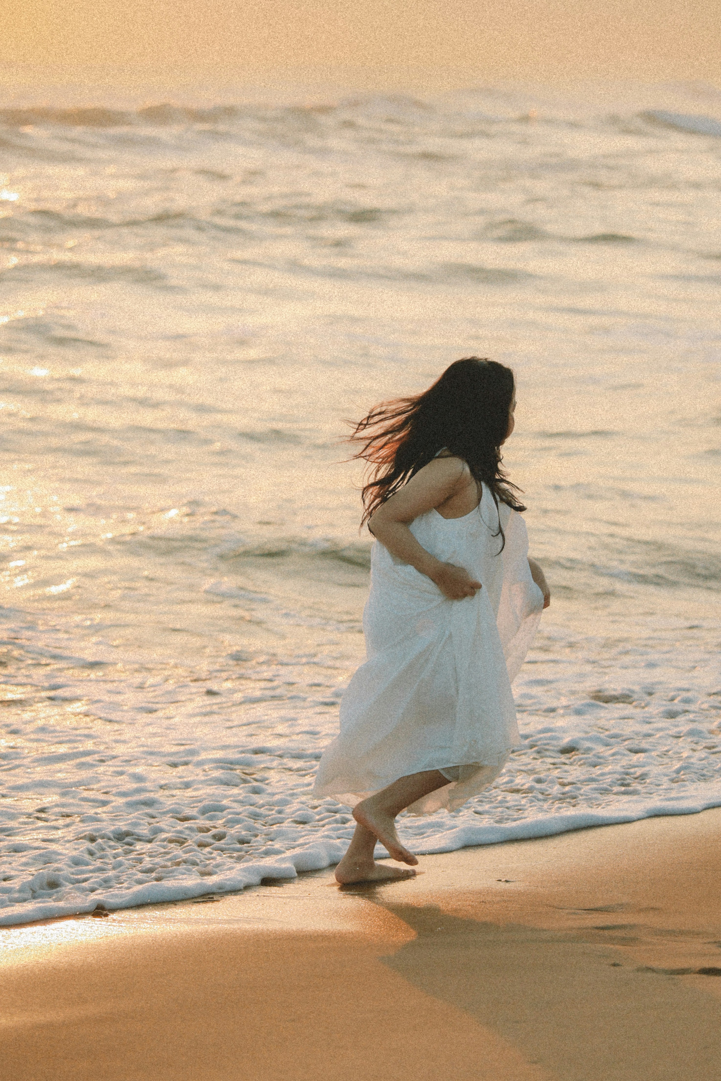 White-dress silhouette on sunlit shoreline