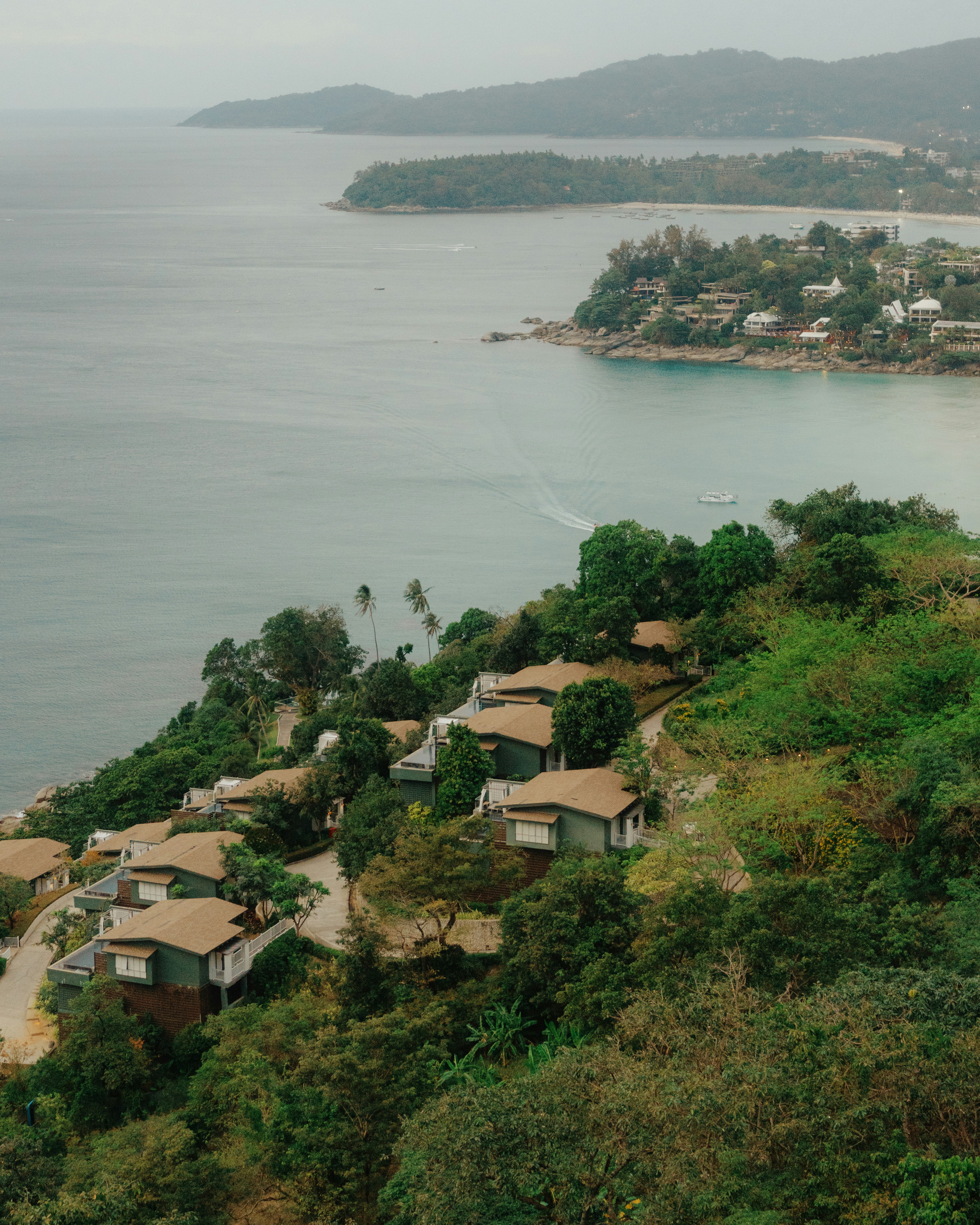 Terraced cottages hugging a verdant hillside above a calm bay