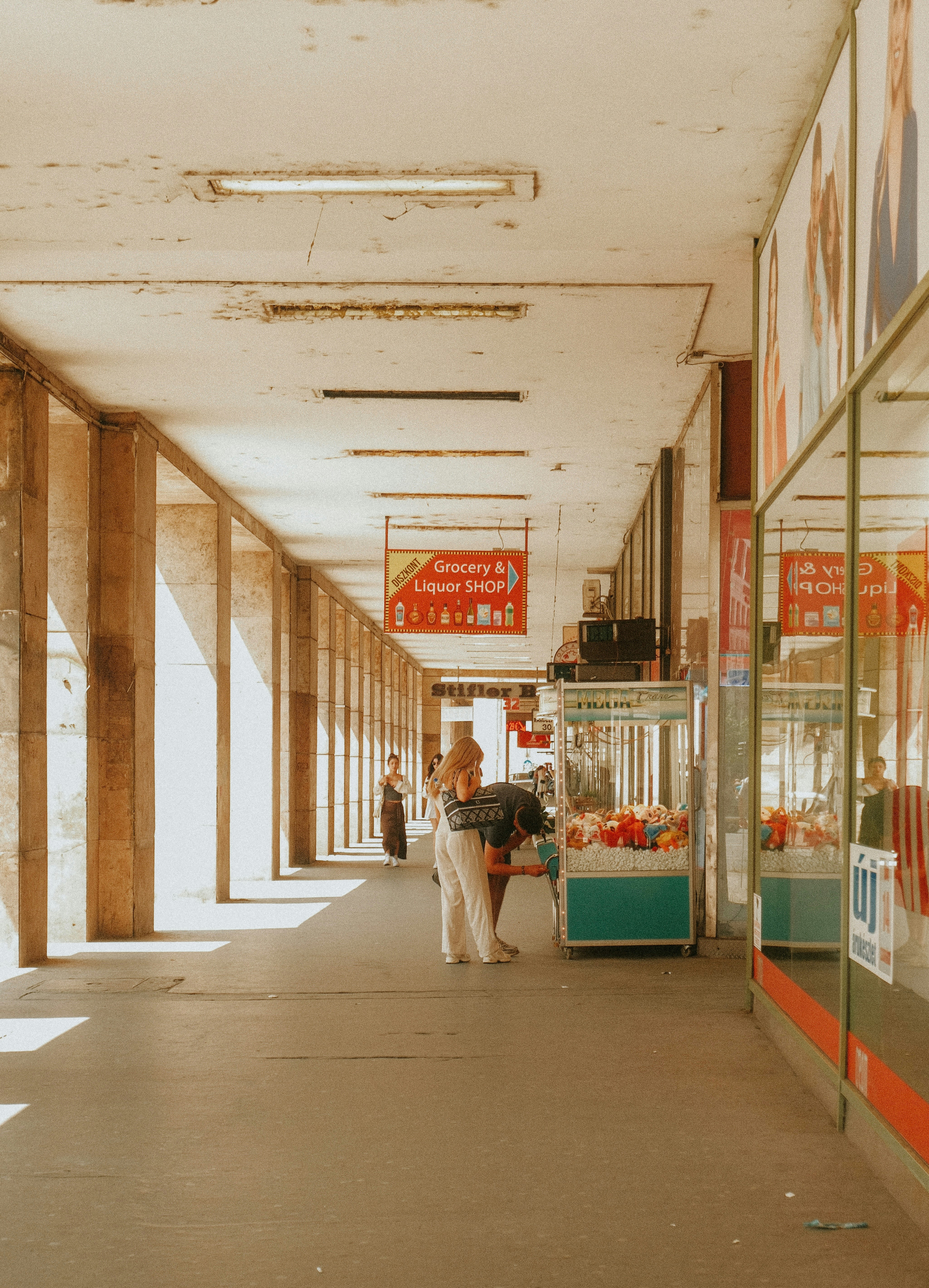 Sunlit Archways and a Quiet Grocery Stand in a Deserted Arcade