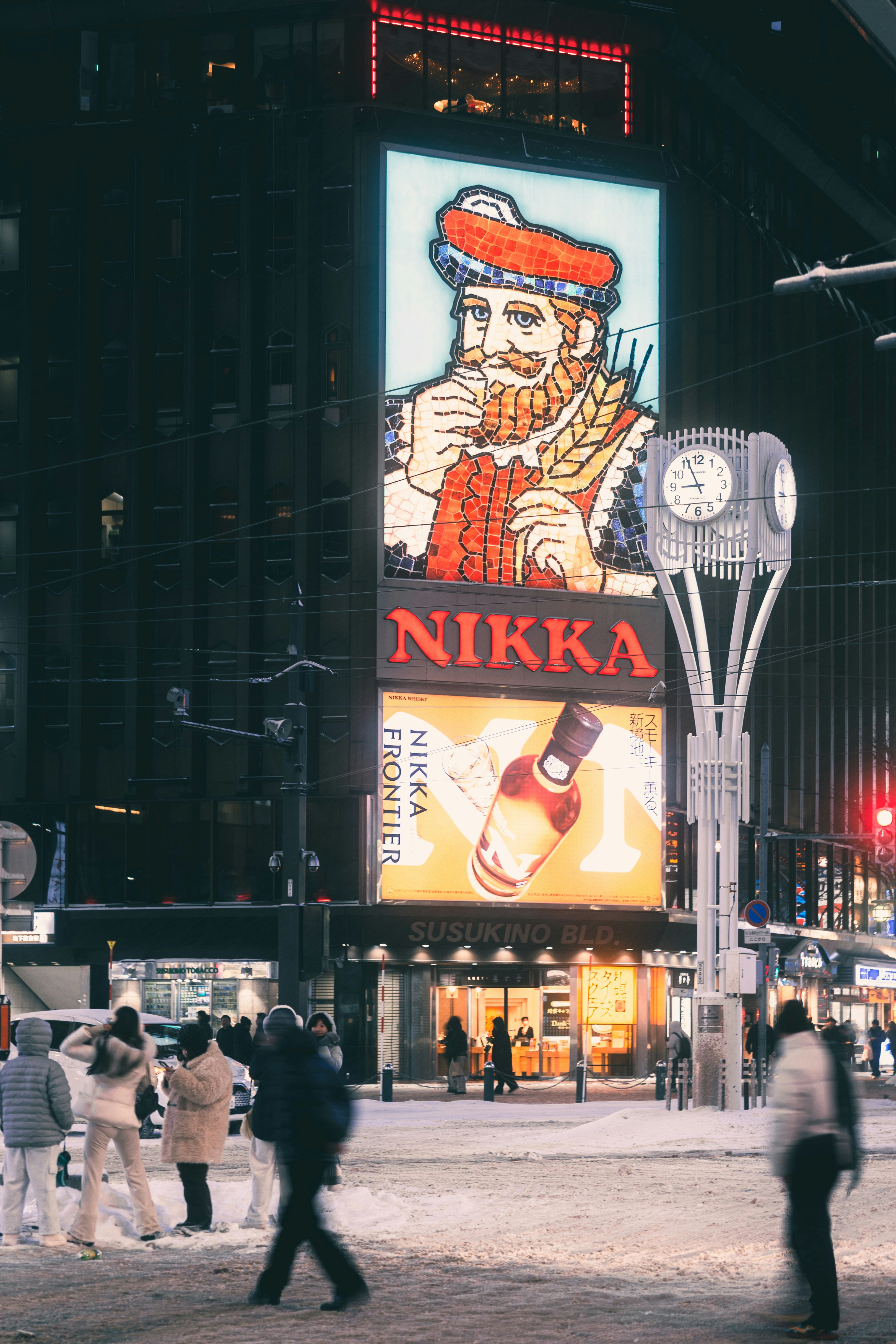 Neon Signage and Snowy Pedestrian Crossing in Front of Nikka Billboard
