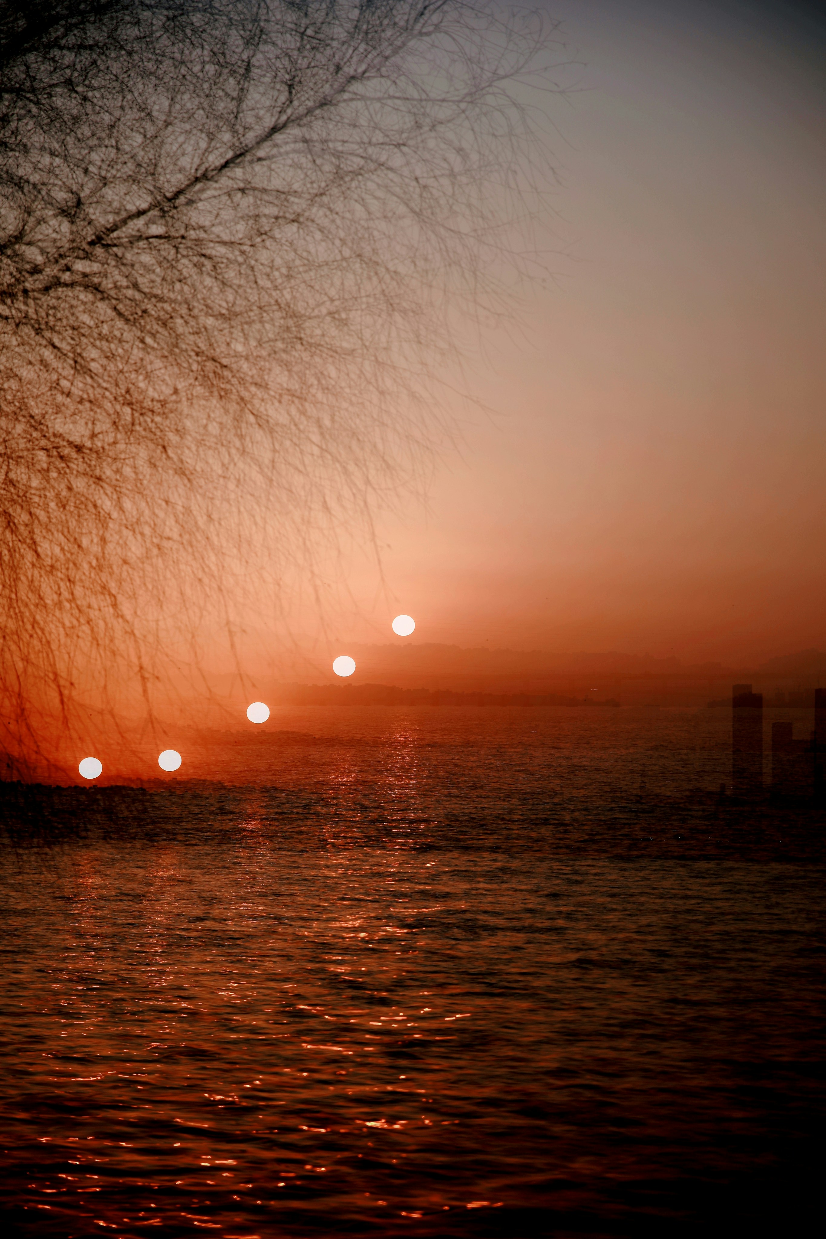 Sunset Over Water: A Row of Orbs Leading the Distant Pier