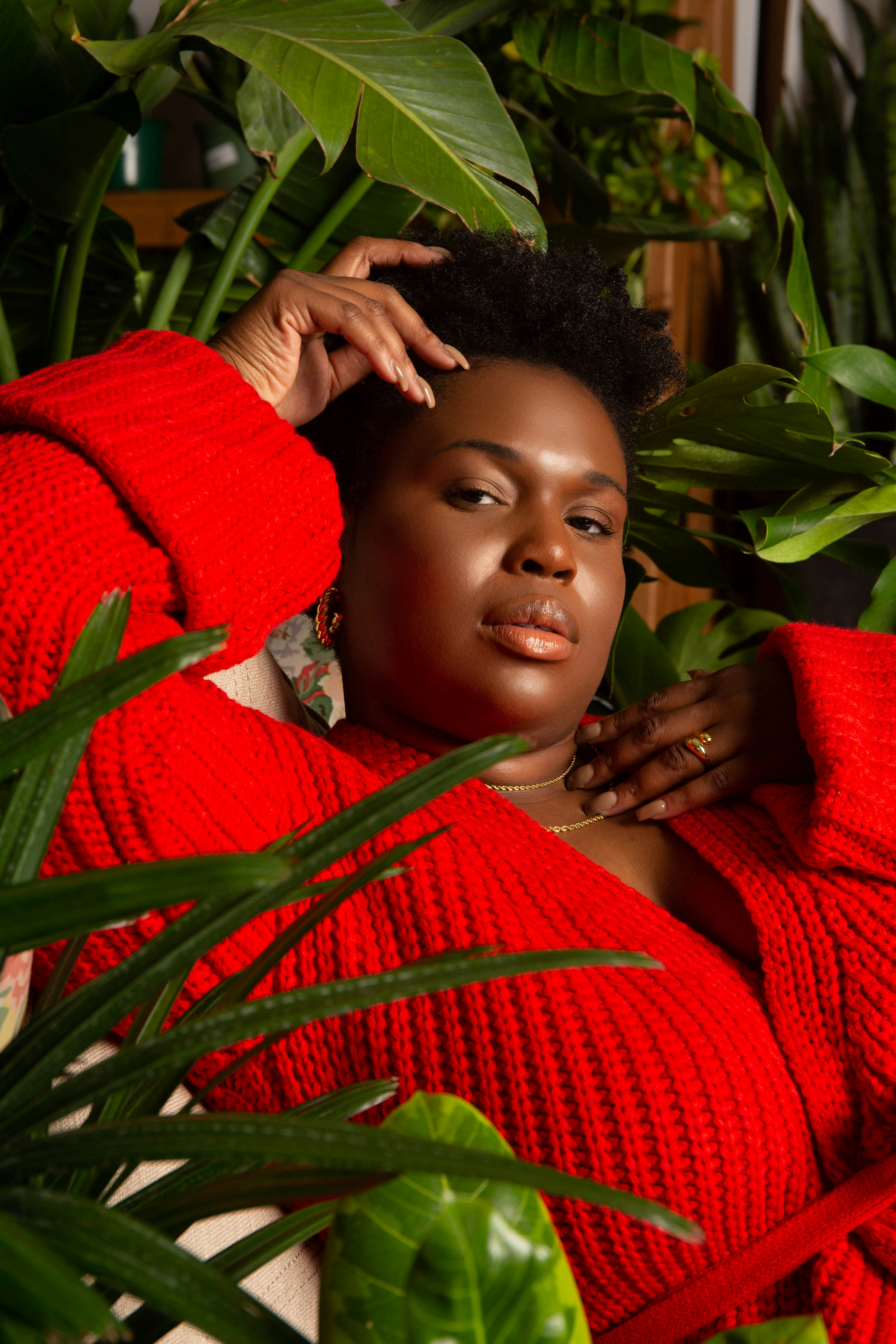 Red Knit Confidence: A Portrait Among Green Foliage