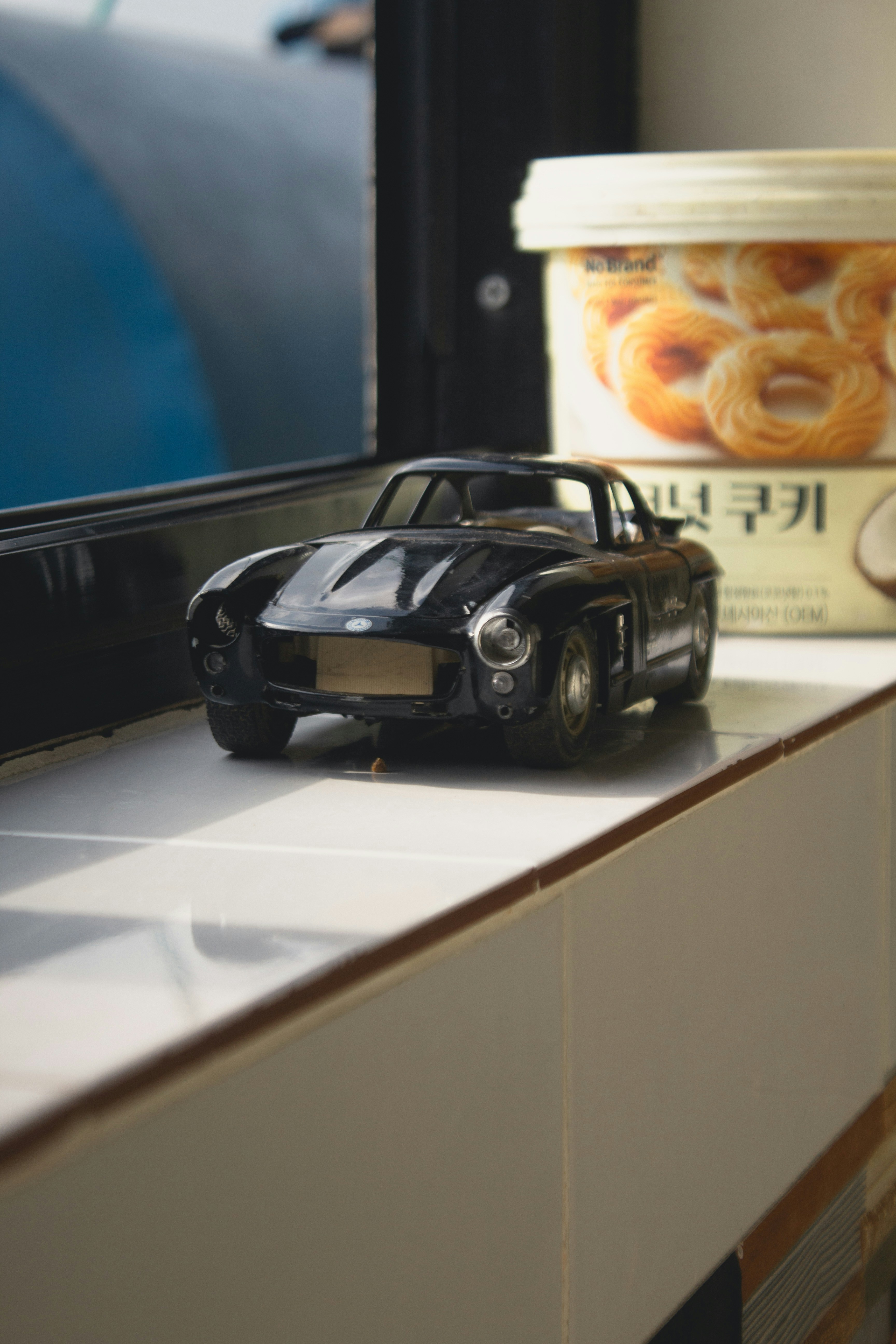 Tiny Black Classic Car models a quiet moment in a sunlit kitchen shelf