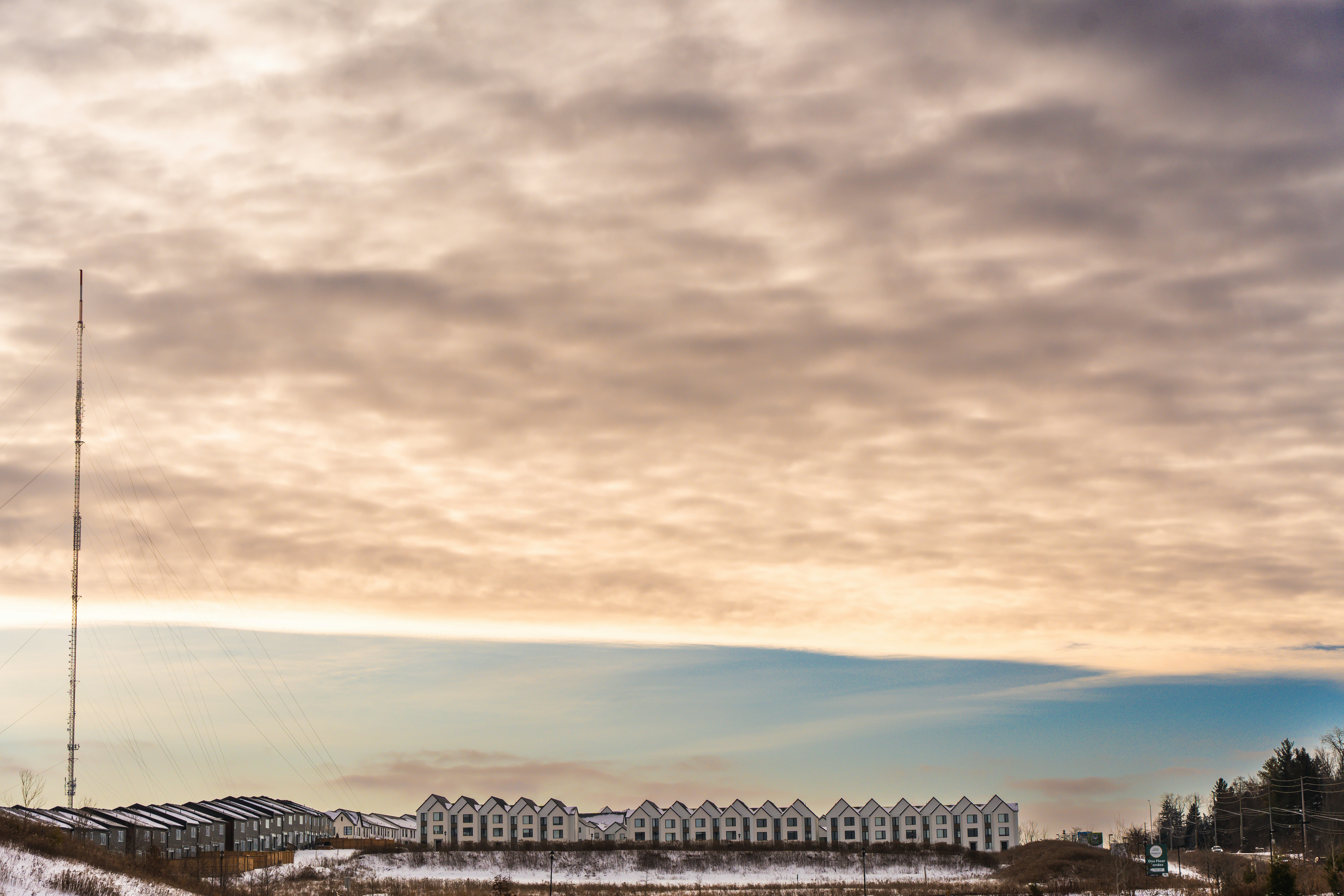 Low-slung row of snow-dusted houses under a dramatic cloudscape