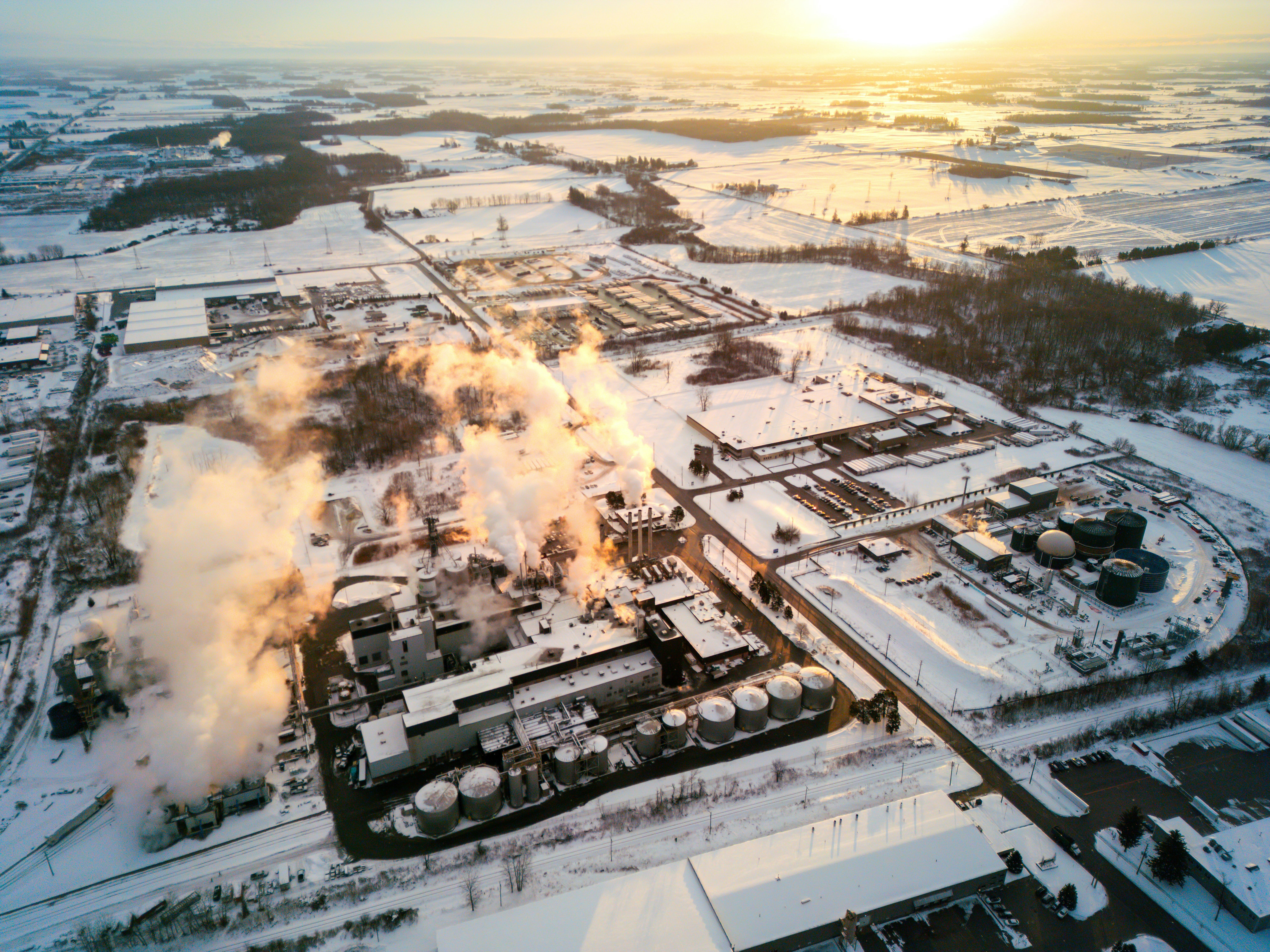 Industrial dawn: steam rising over a snow-swept plant