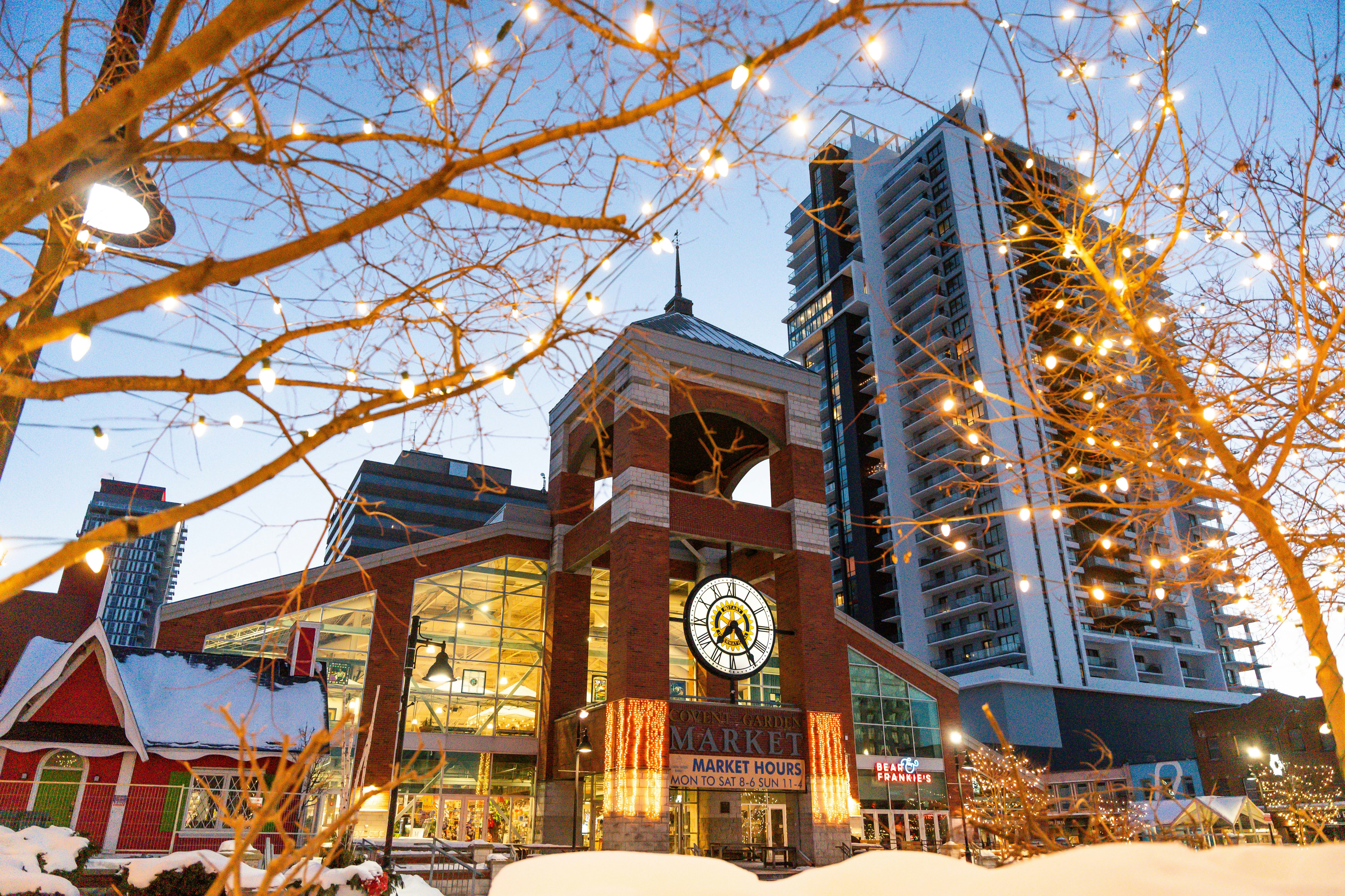 Market Clock at Twilight: Snow, Lights, and Modern Towers
