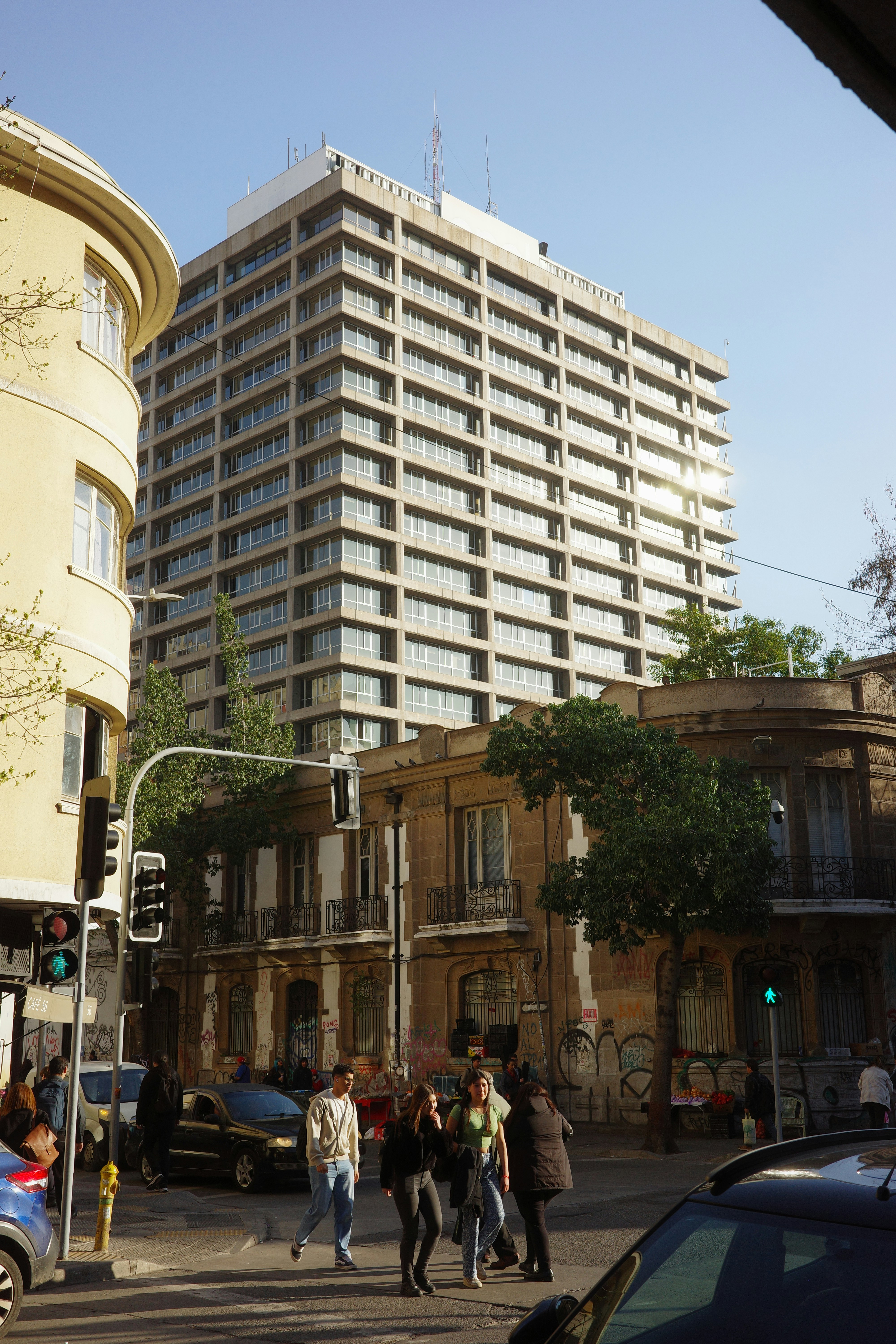 Tall modern building overlooks older structures and street.