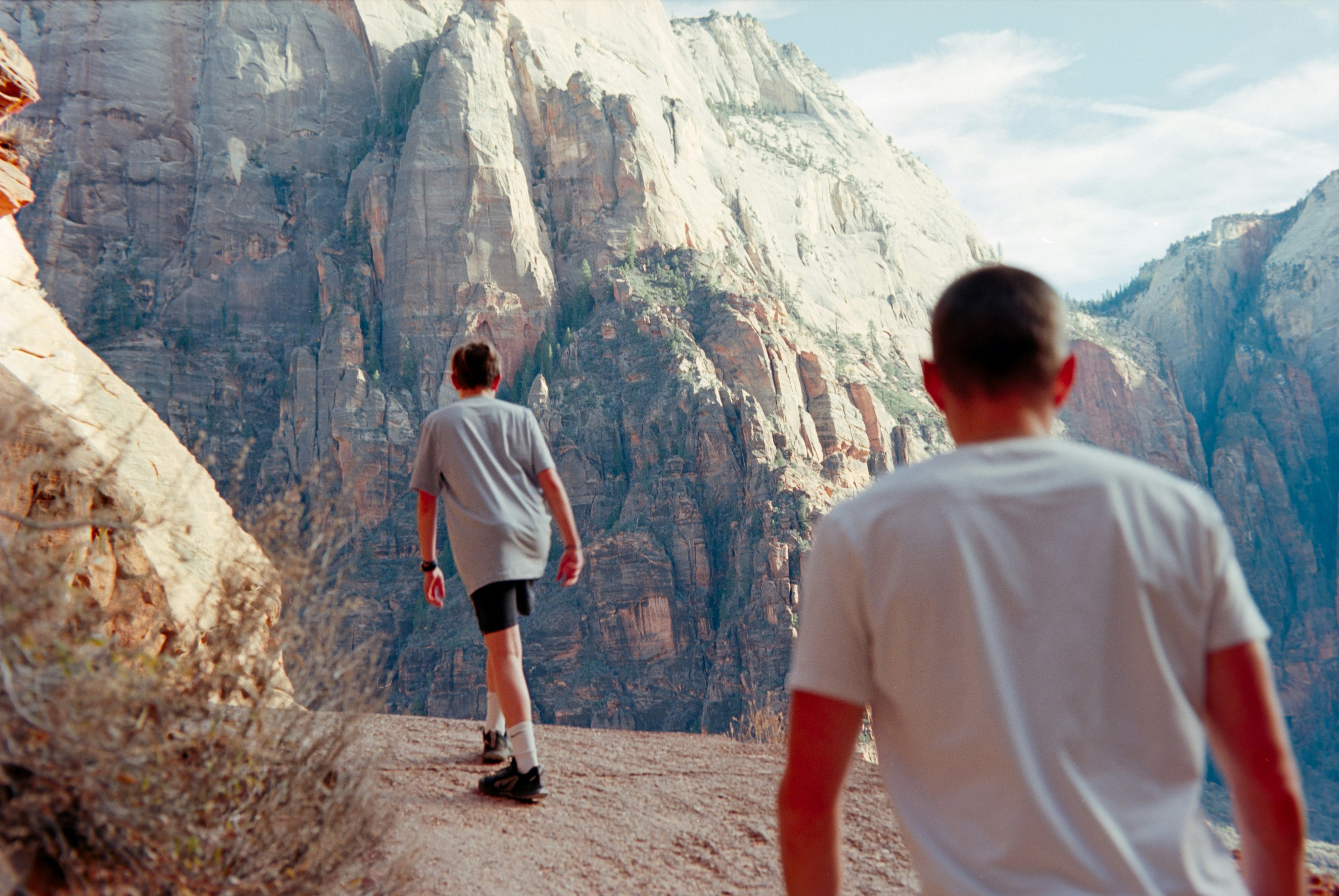Toward the Canyon Edge: Two Travelers Against Monumental Cliffs